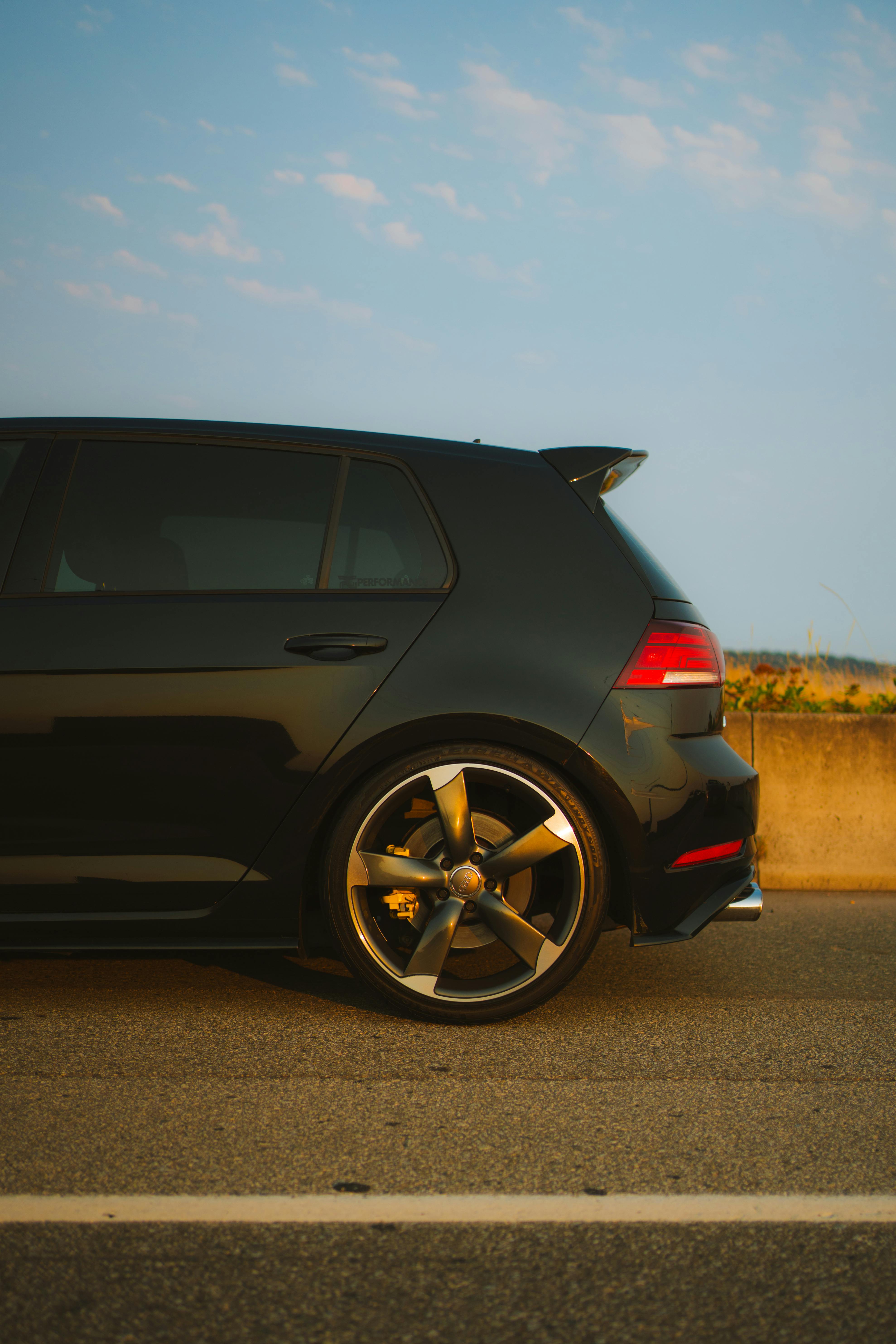A black golf r on the road with the sun setting · Free Stock Photo