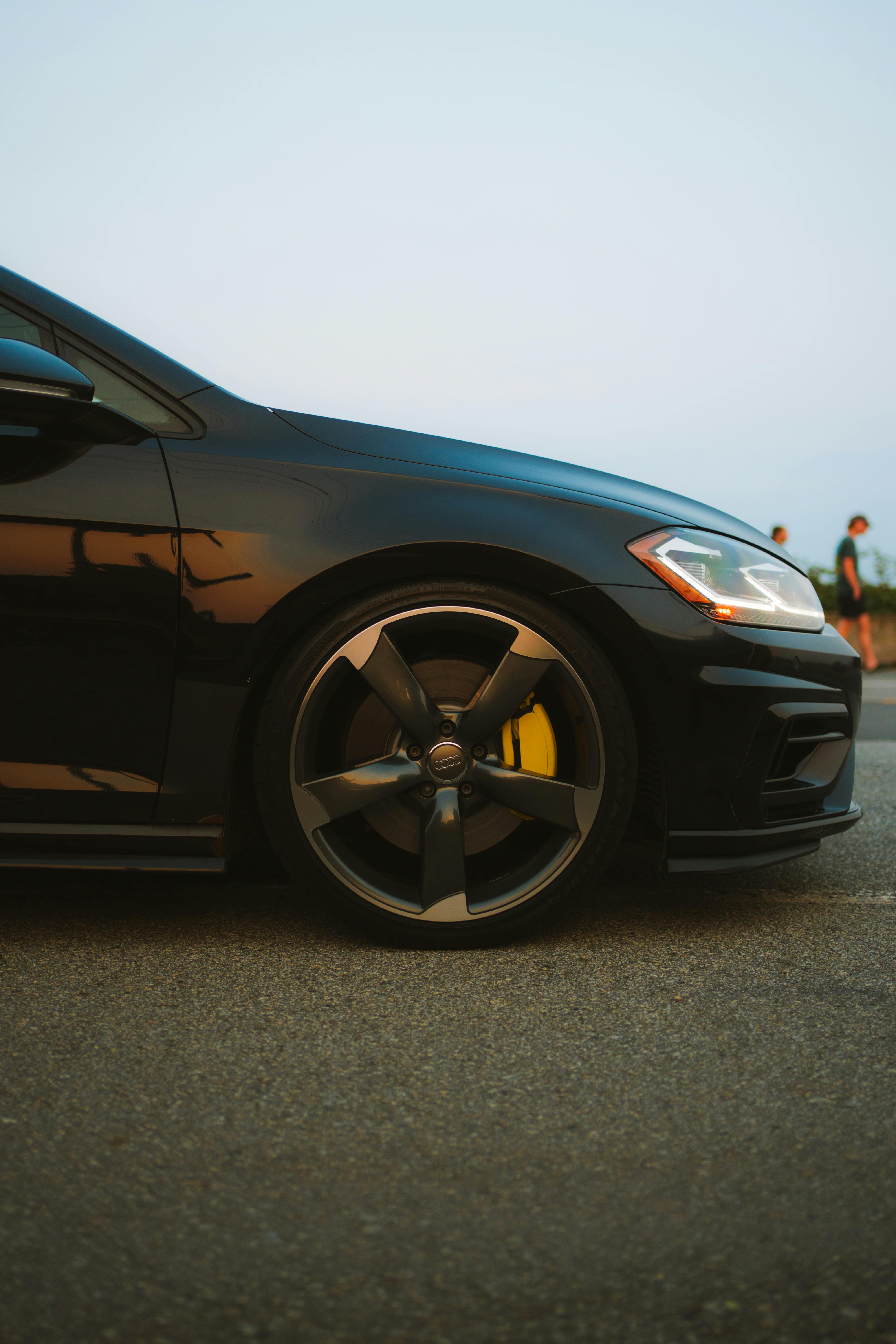 A black car with yellow rims on the road · Free Stock Photo