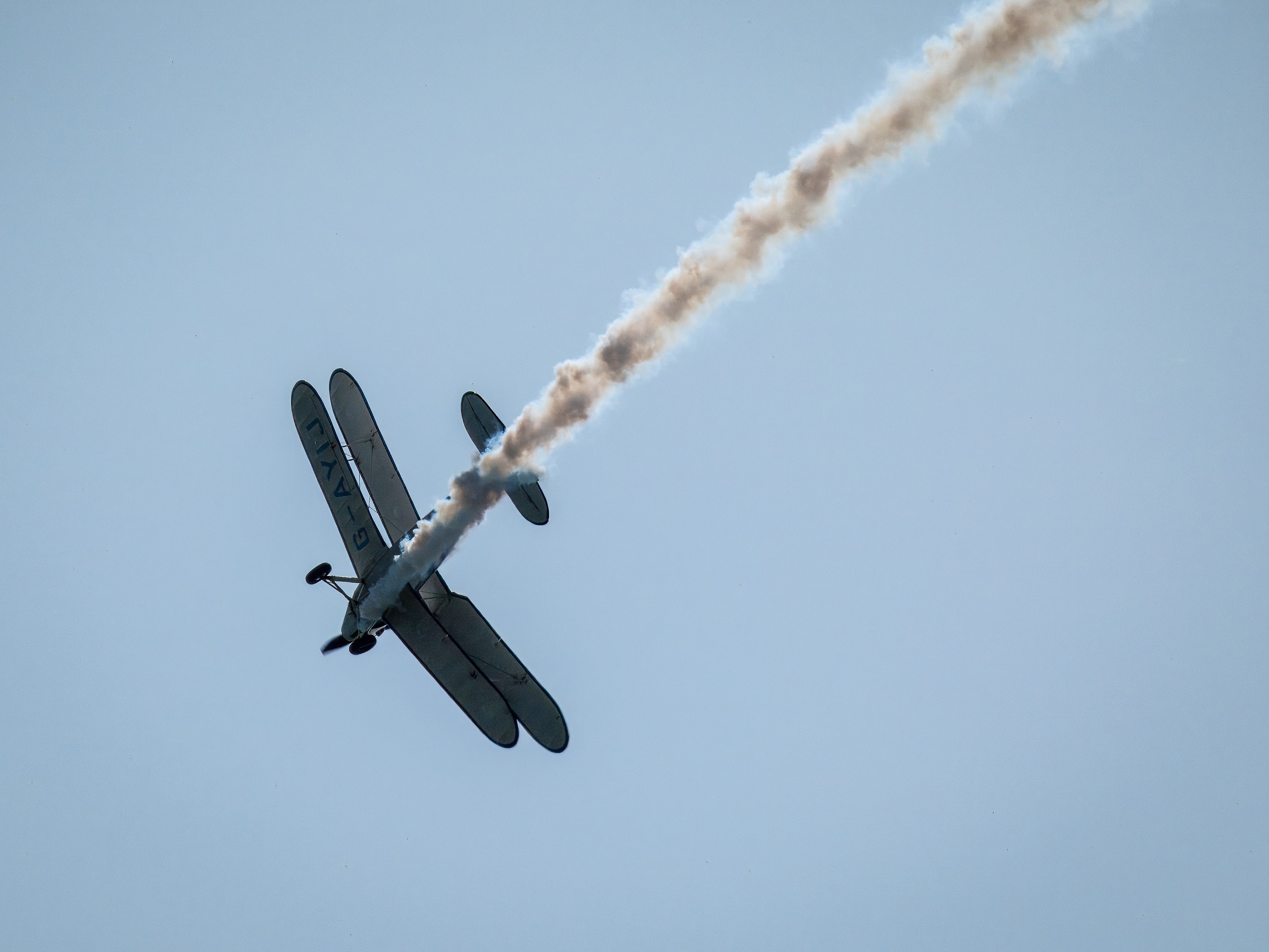 A small airplane flying through the air with smoke coming out of it ...