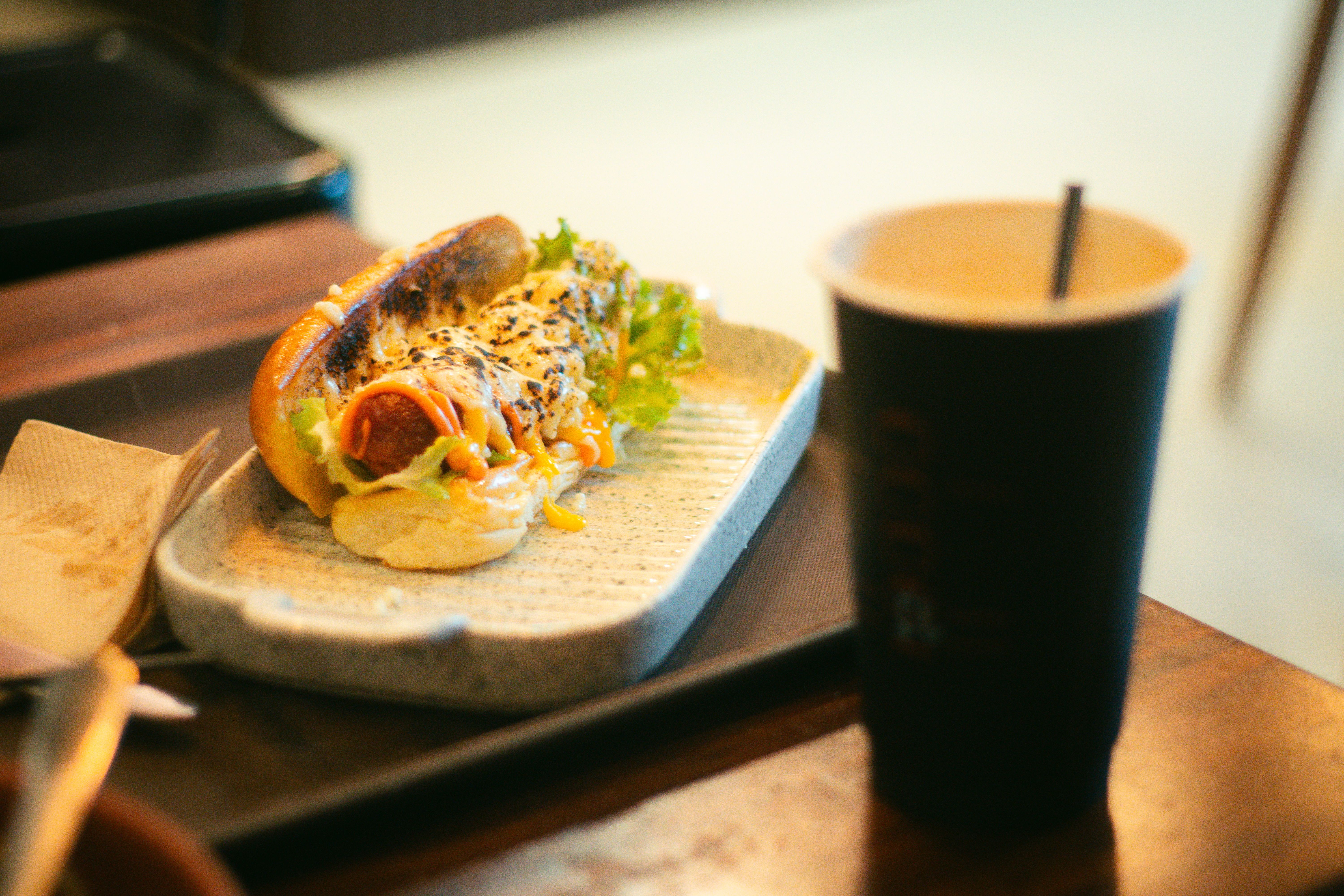 A hot dog on a plate with a drink next to it · Free Stock Photo