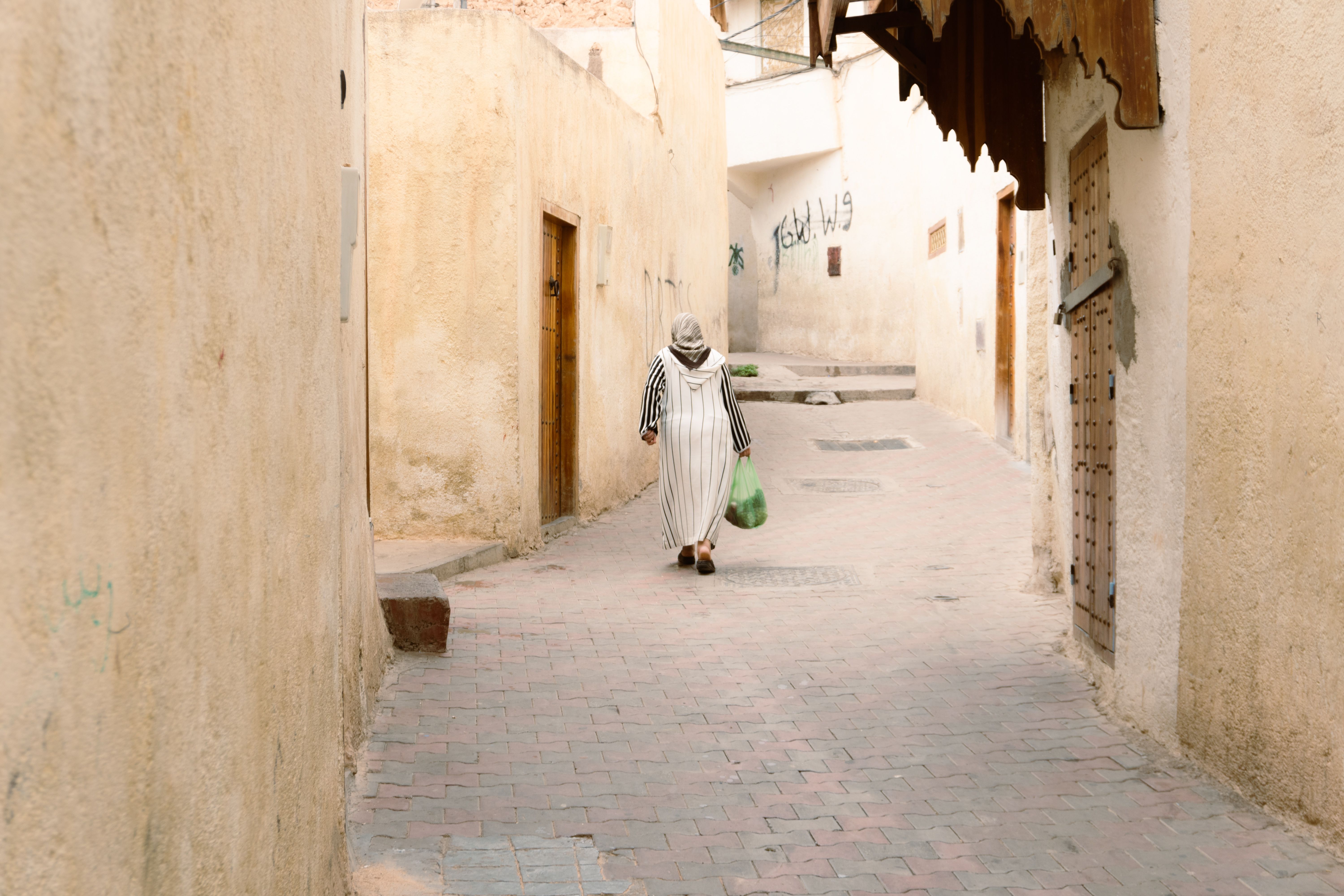 A woman walking down a narrow alleyway in the middle of the day · Free ...