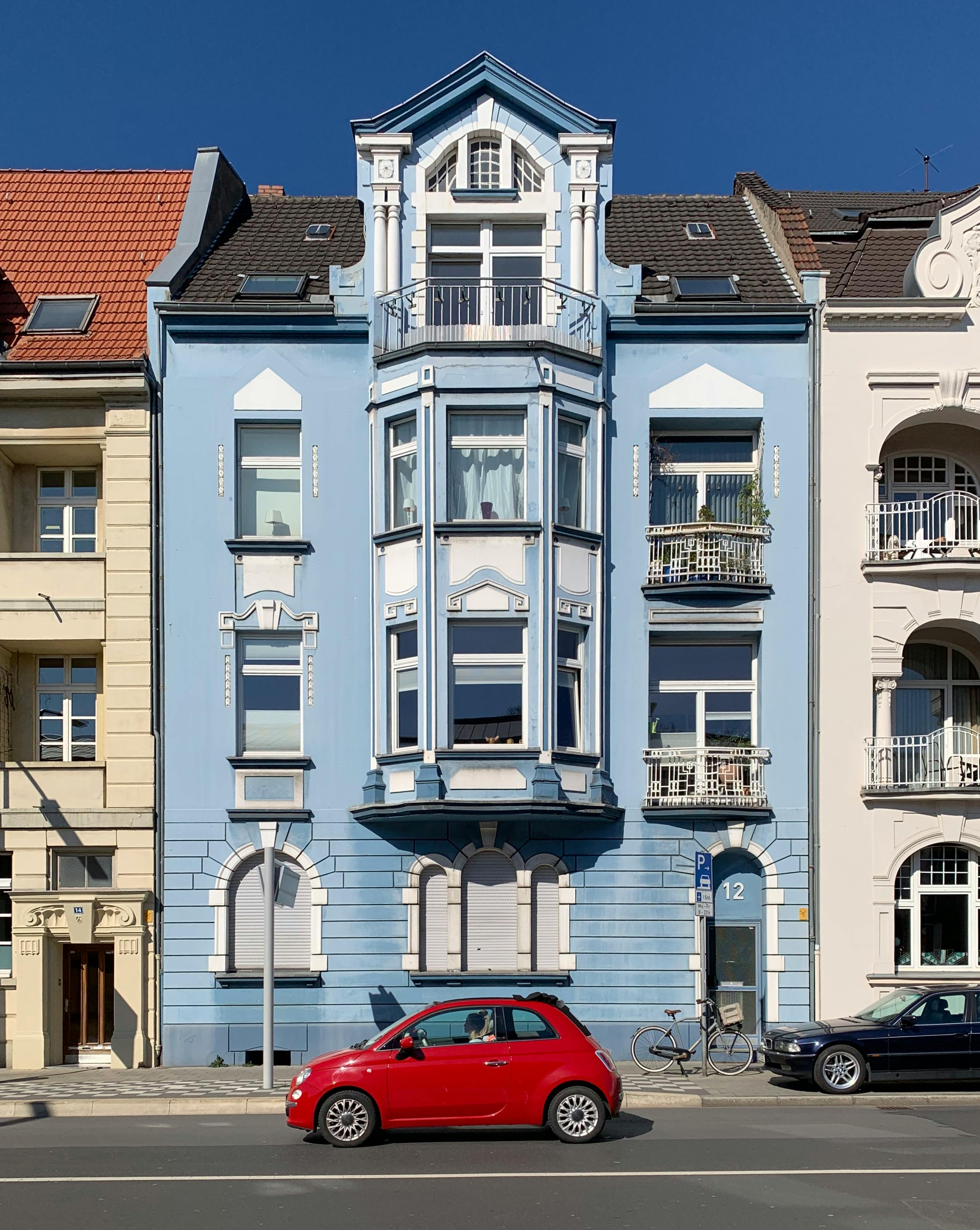 A car is parked in front of a blue building · Free Stock Photo