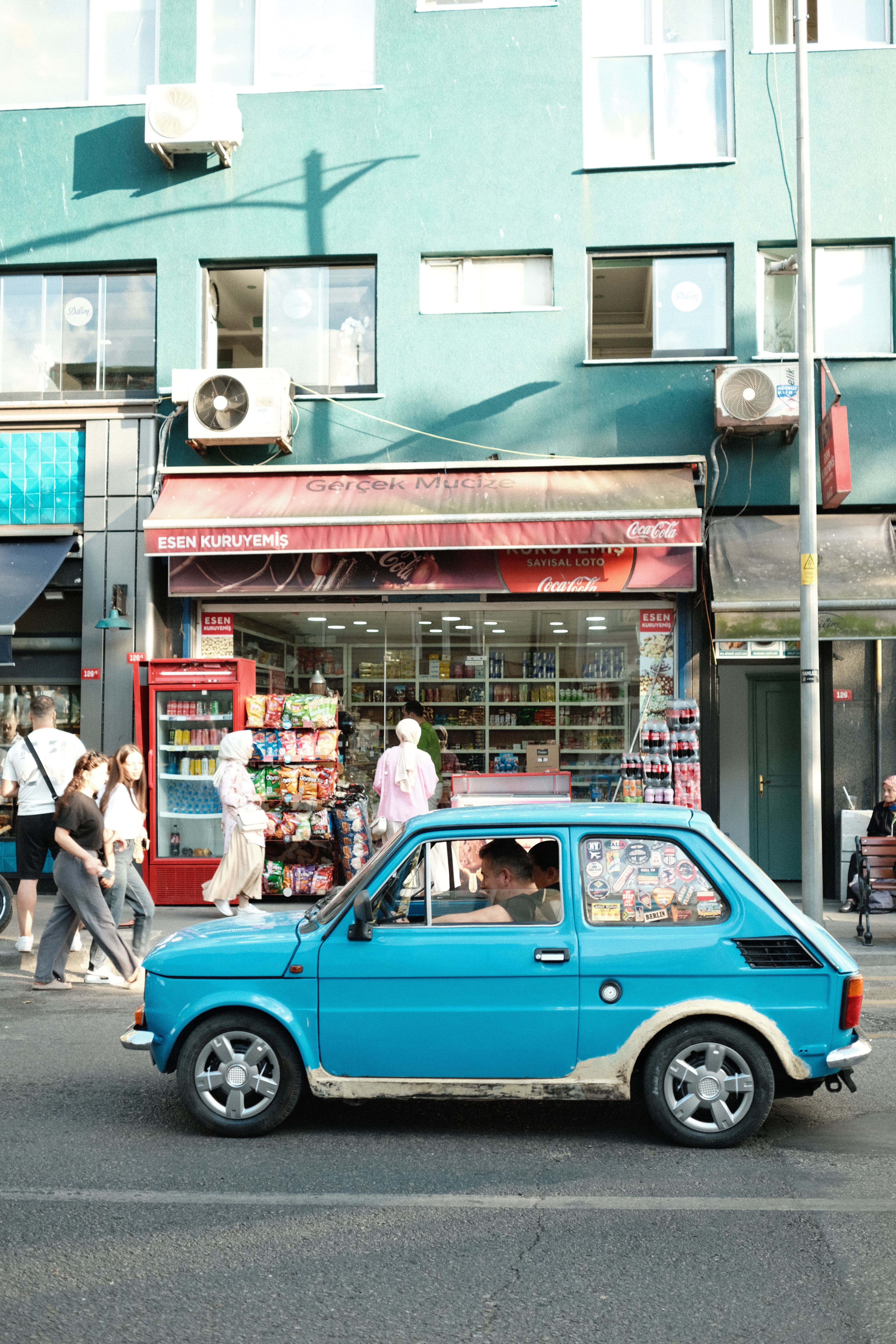 A small blue car is parked in front of a store · Free Stock Photo
