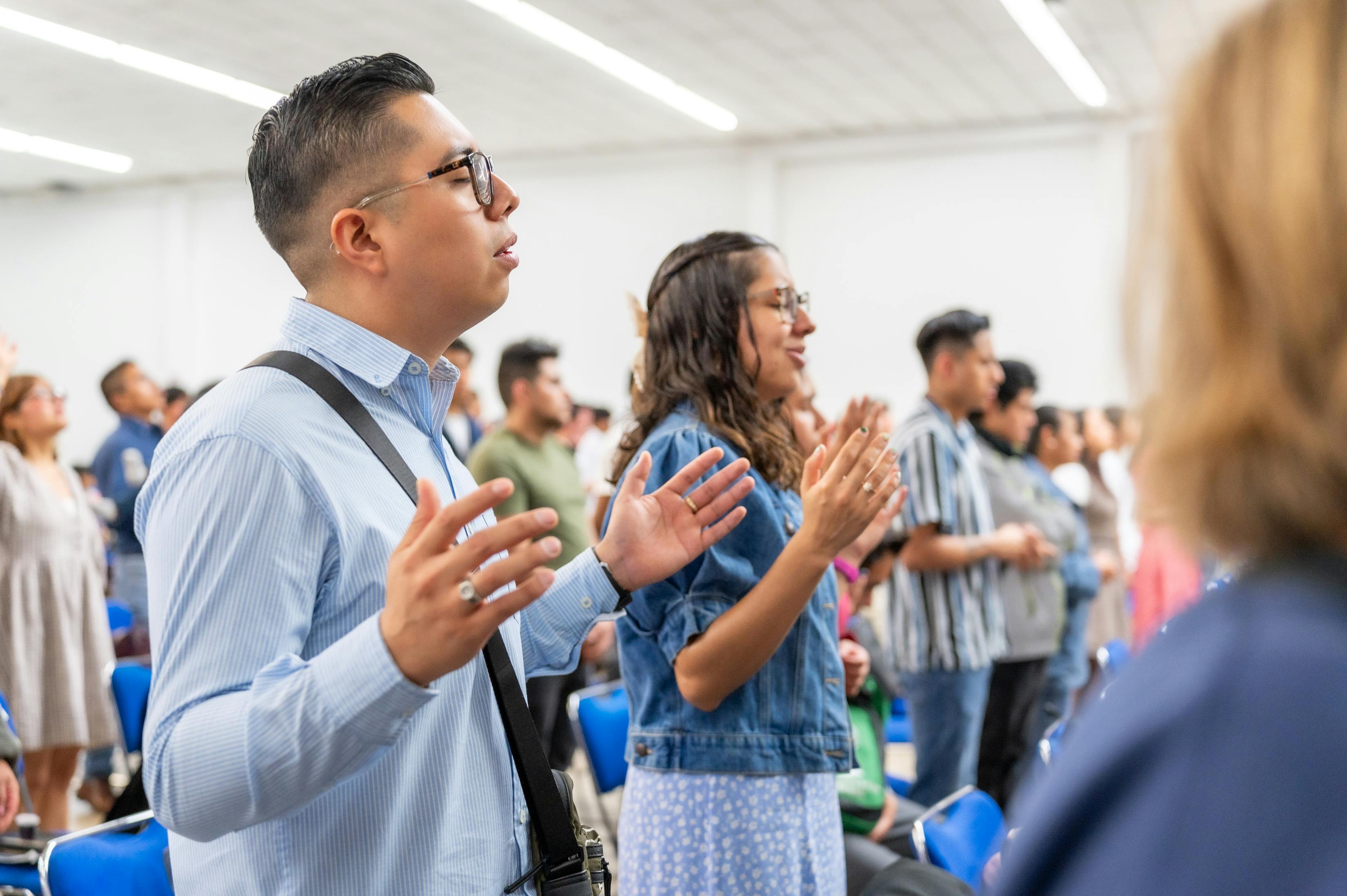 A group of people standing in a room clapping · Free Stock Photo