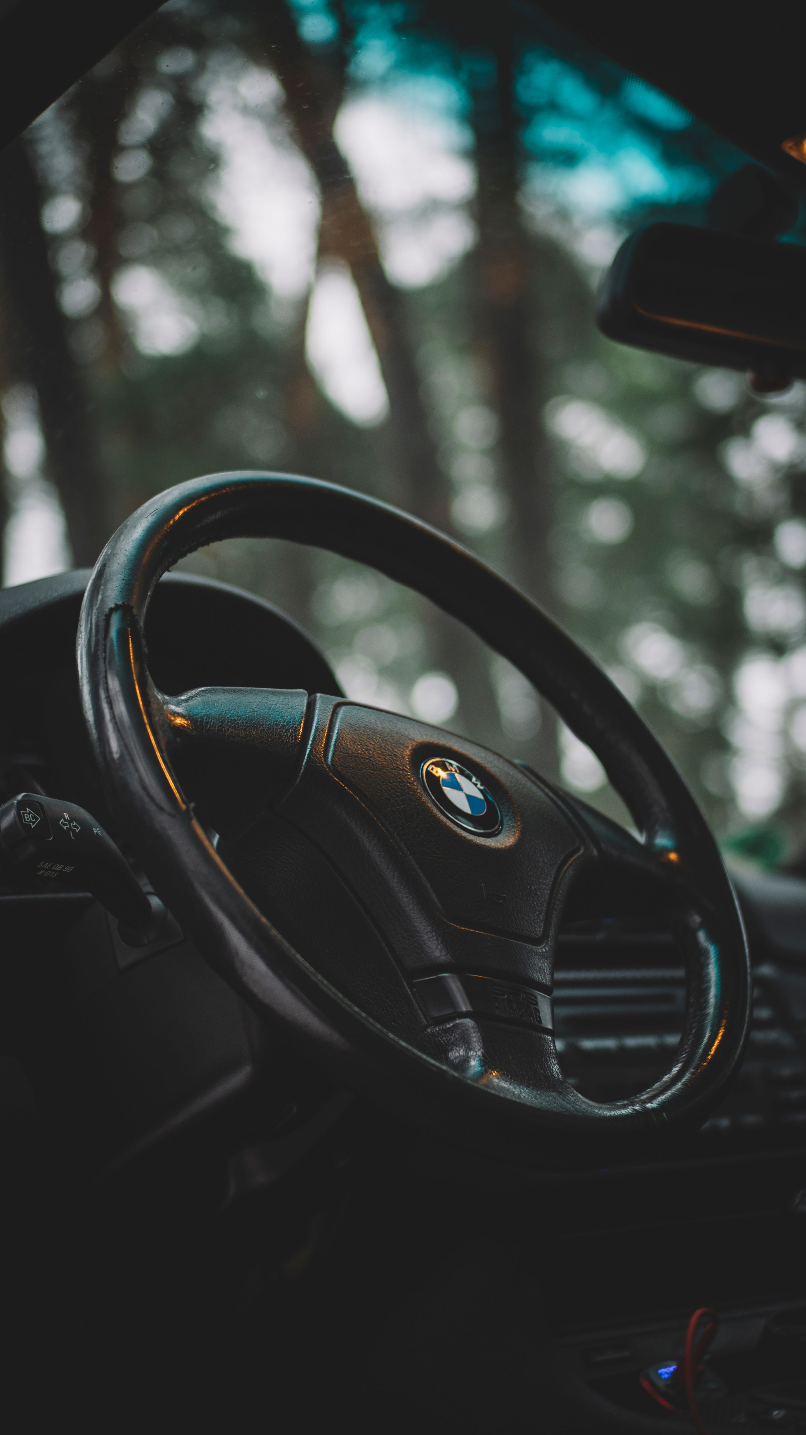 A car dashboard with a steering wheel and a tree · Free Stock Photo