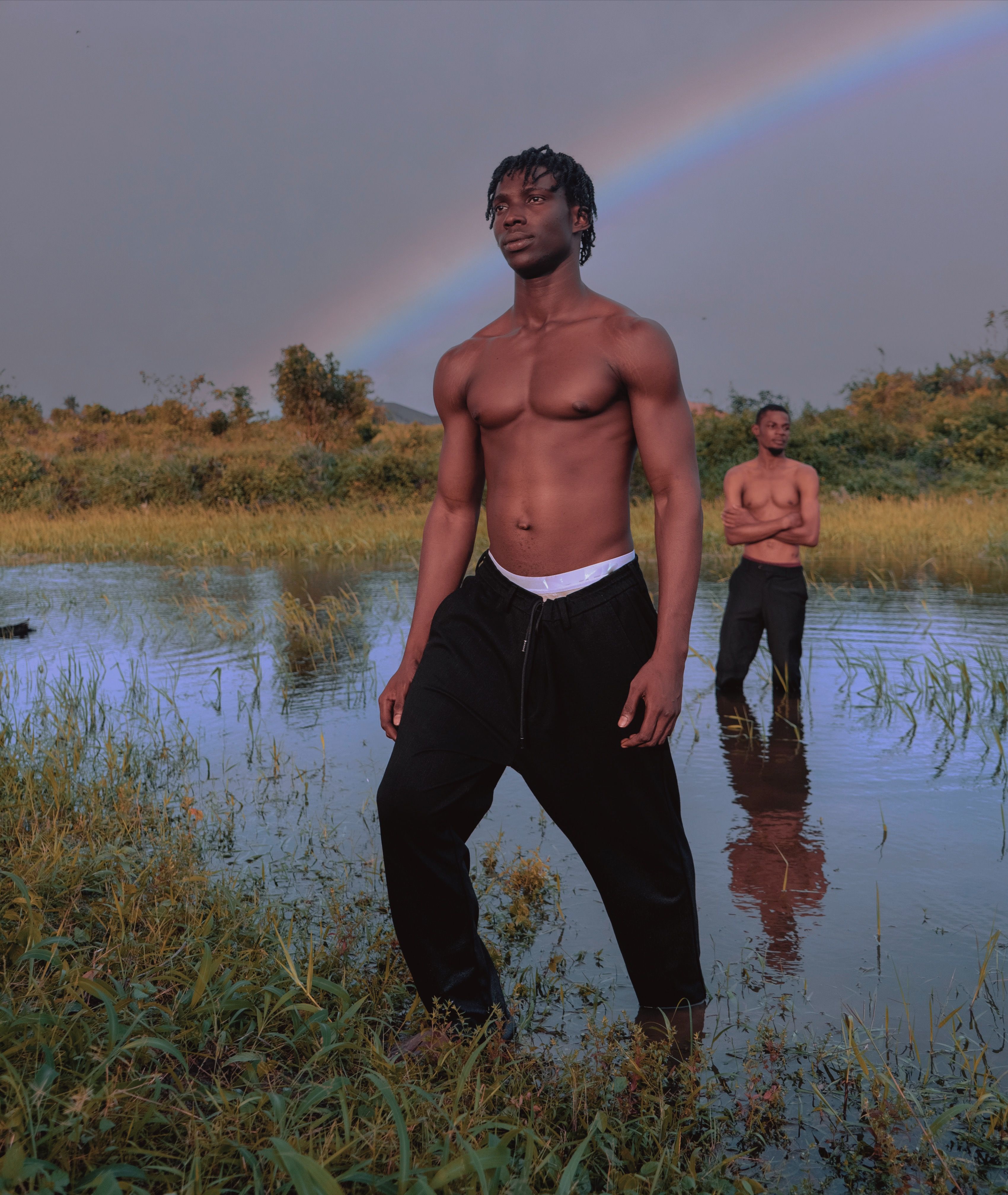 Two men standing in the water with a rainbow in the background · Free ...