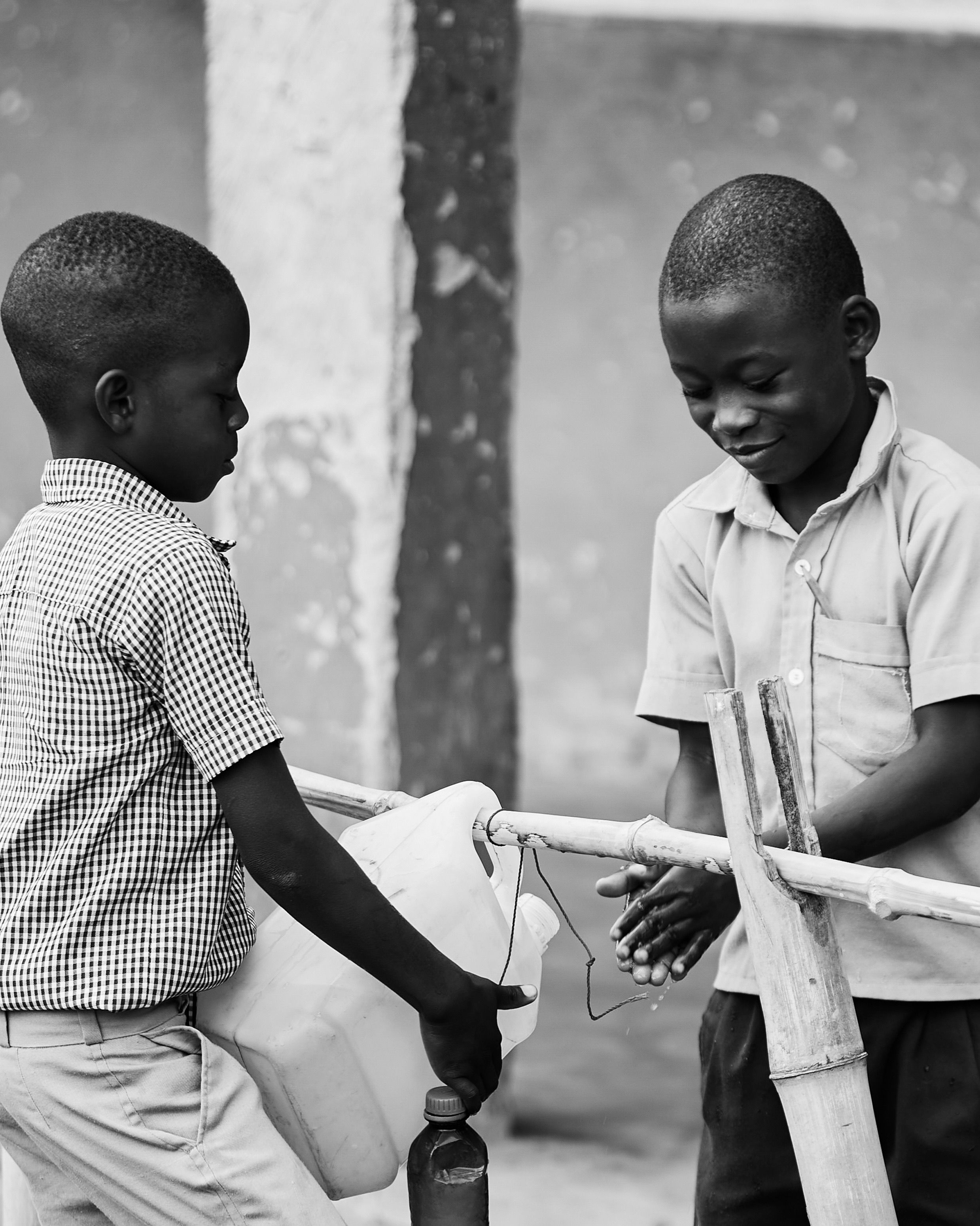 Children Washing Hands From a Bottle on a Rack · Free Stock Photo