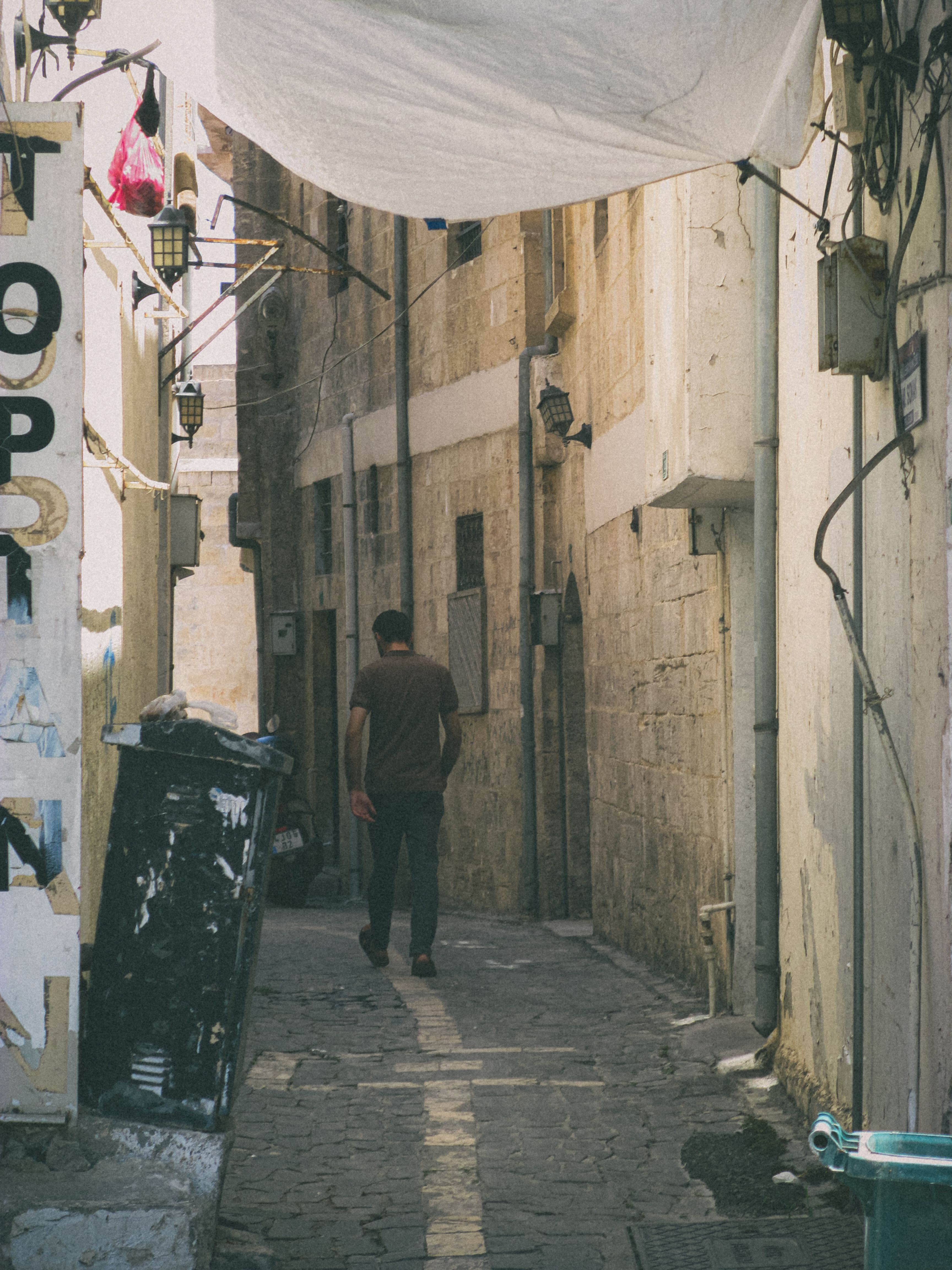 A man walking down a narrow alleyway · Free Stock Photo