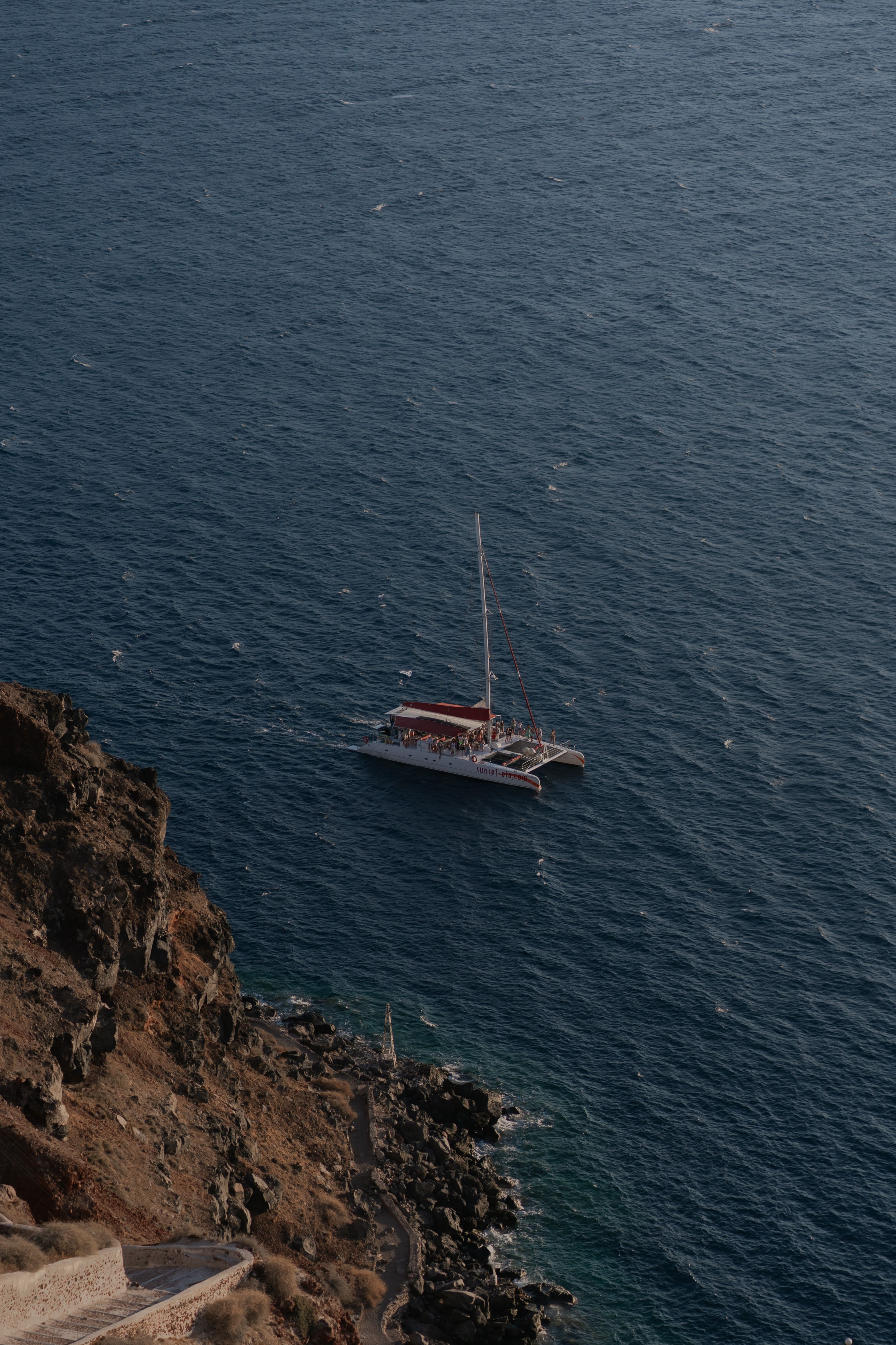 A boat is sailing in the ocean near a cliff · Free Stock Photo