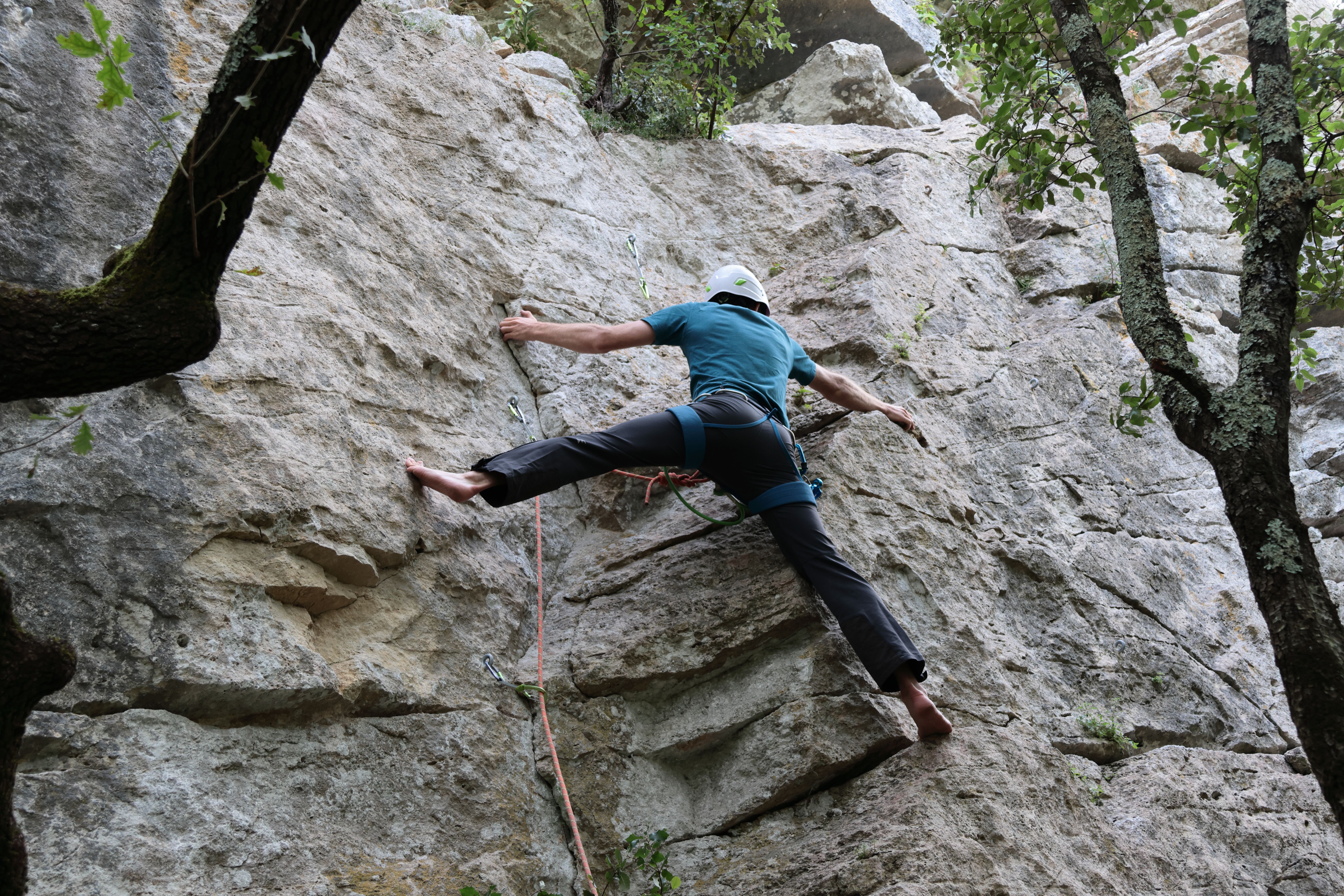 A man climbing up a rock face in the woods · Free Stock Photo