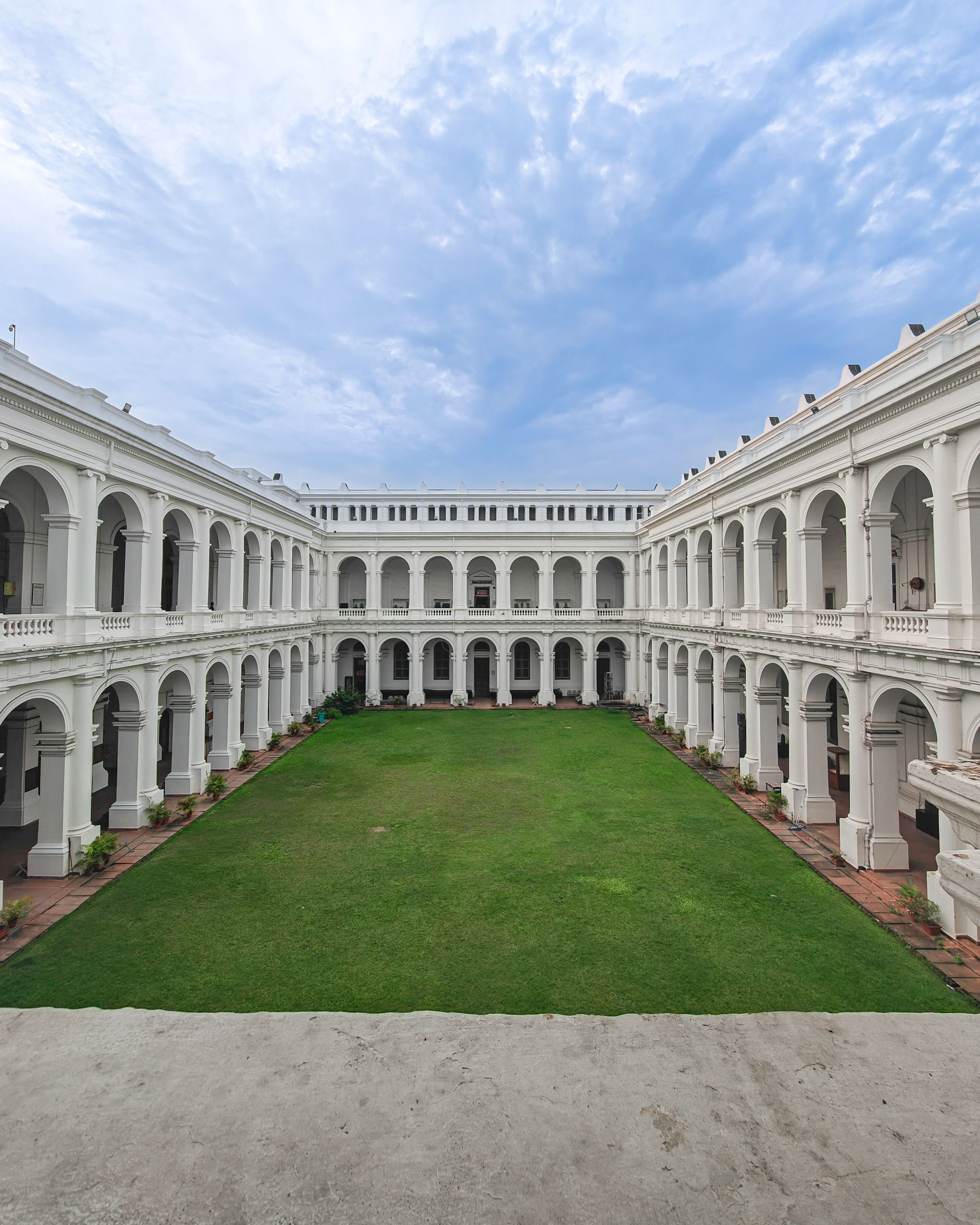 The courtyard of a large building with green grass · Free Stock Photo