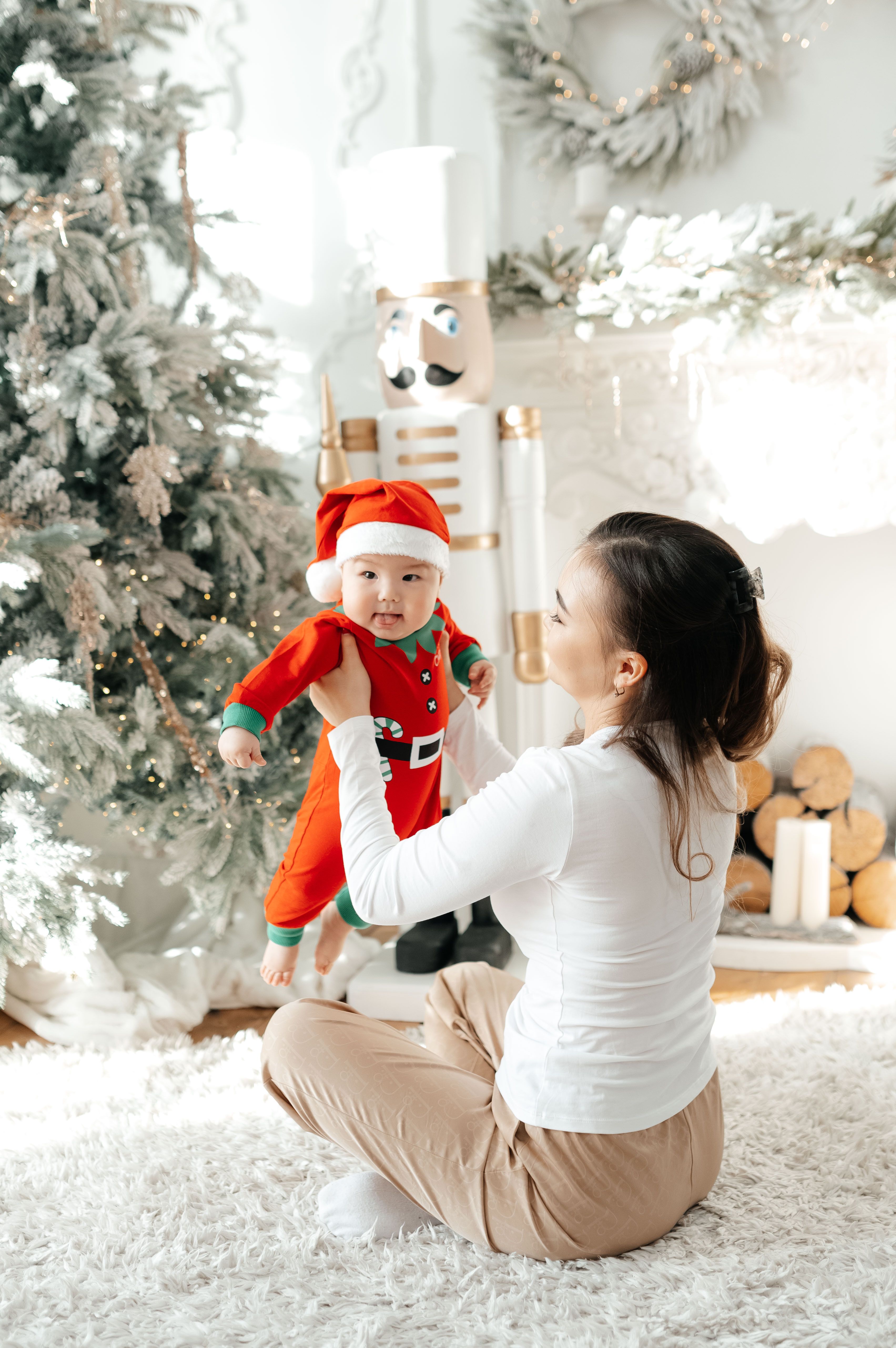 Mother Playing with a Baby in an Elf Costume by the Christmas Tree ...