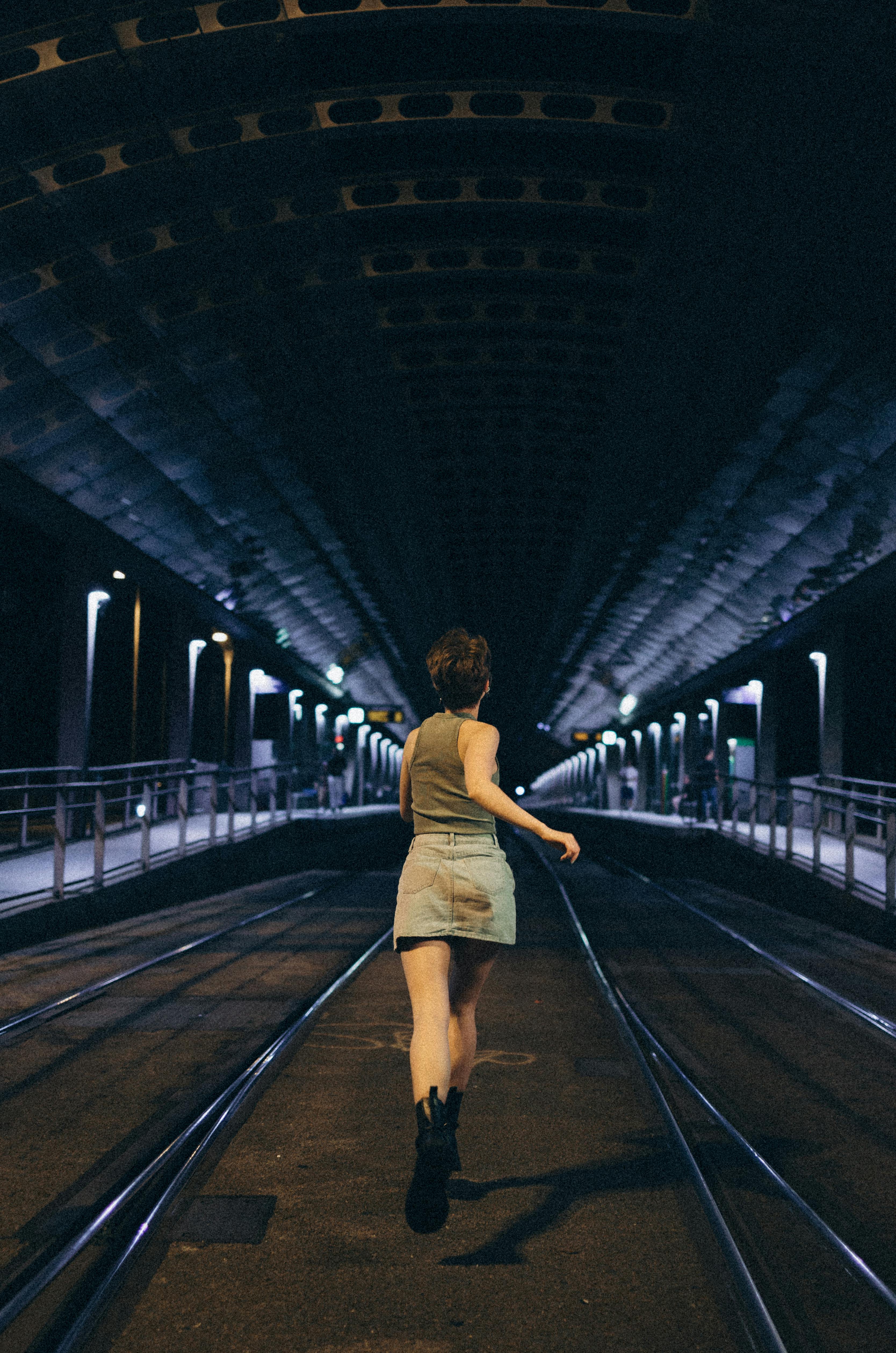 A woman walking on a train track at night · Free Stock Photo