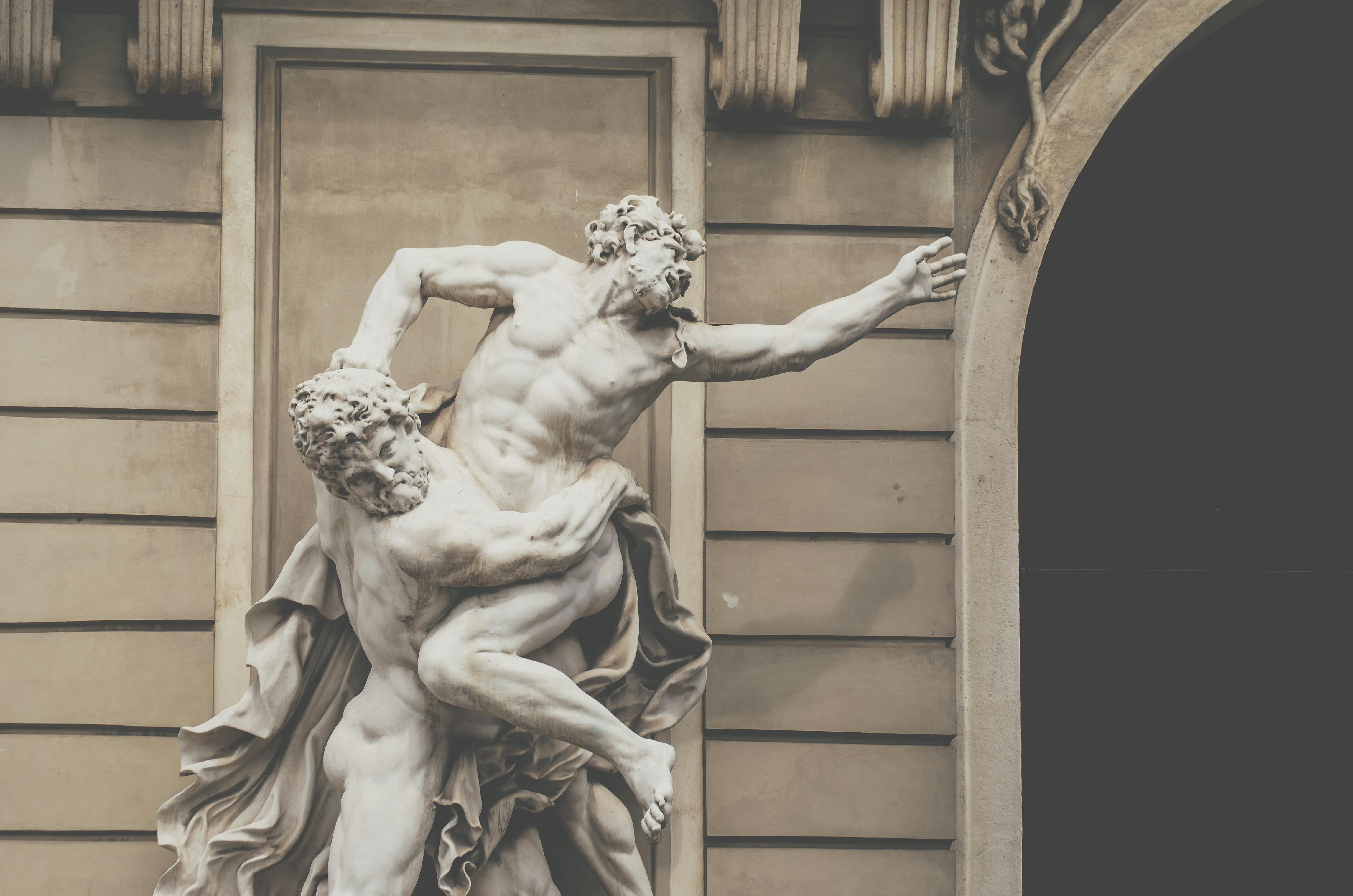 A statue of two men fighting on top of a building · Free Stock Photo