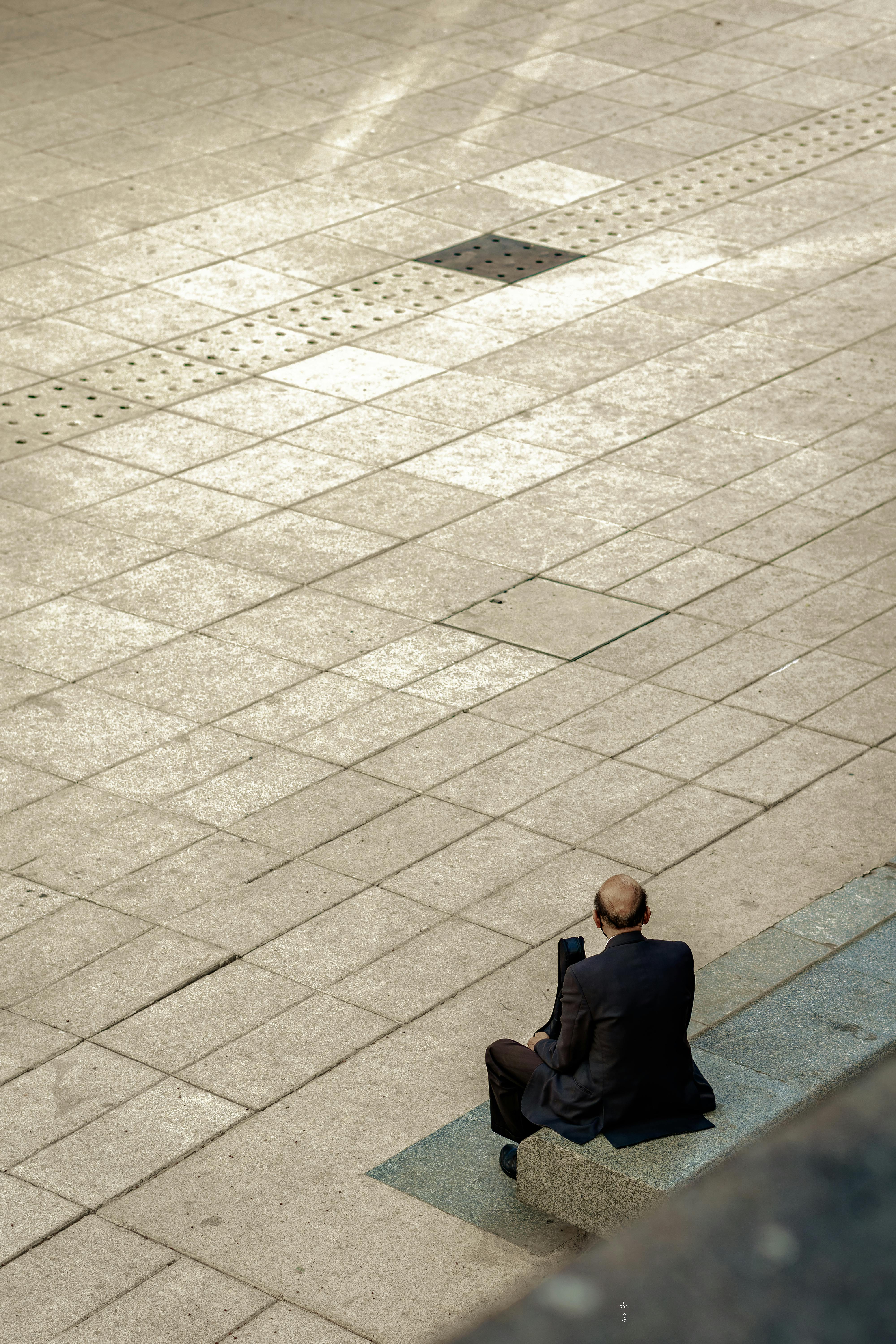 Man Sitting on a Bench in a City Square · Free Stock Photo