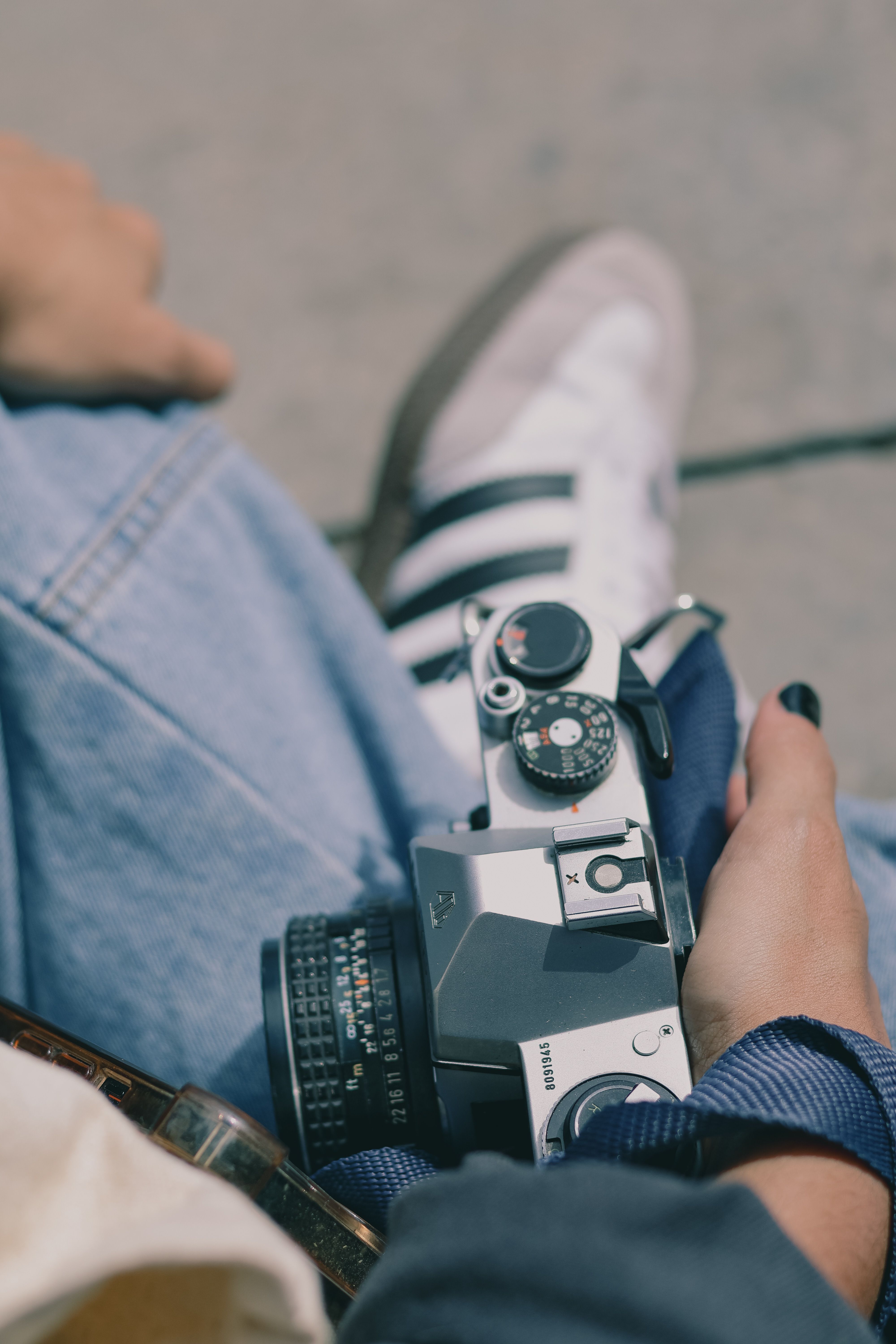 A person holding a camera and wearing jeans · Free Stock Photo