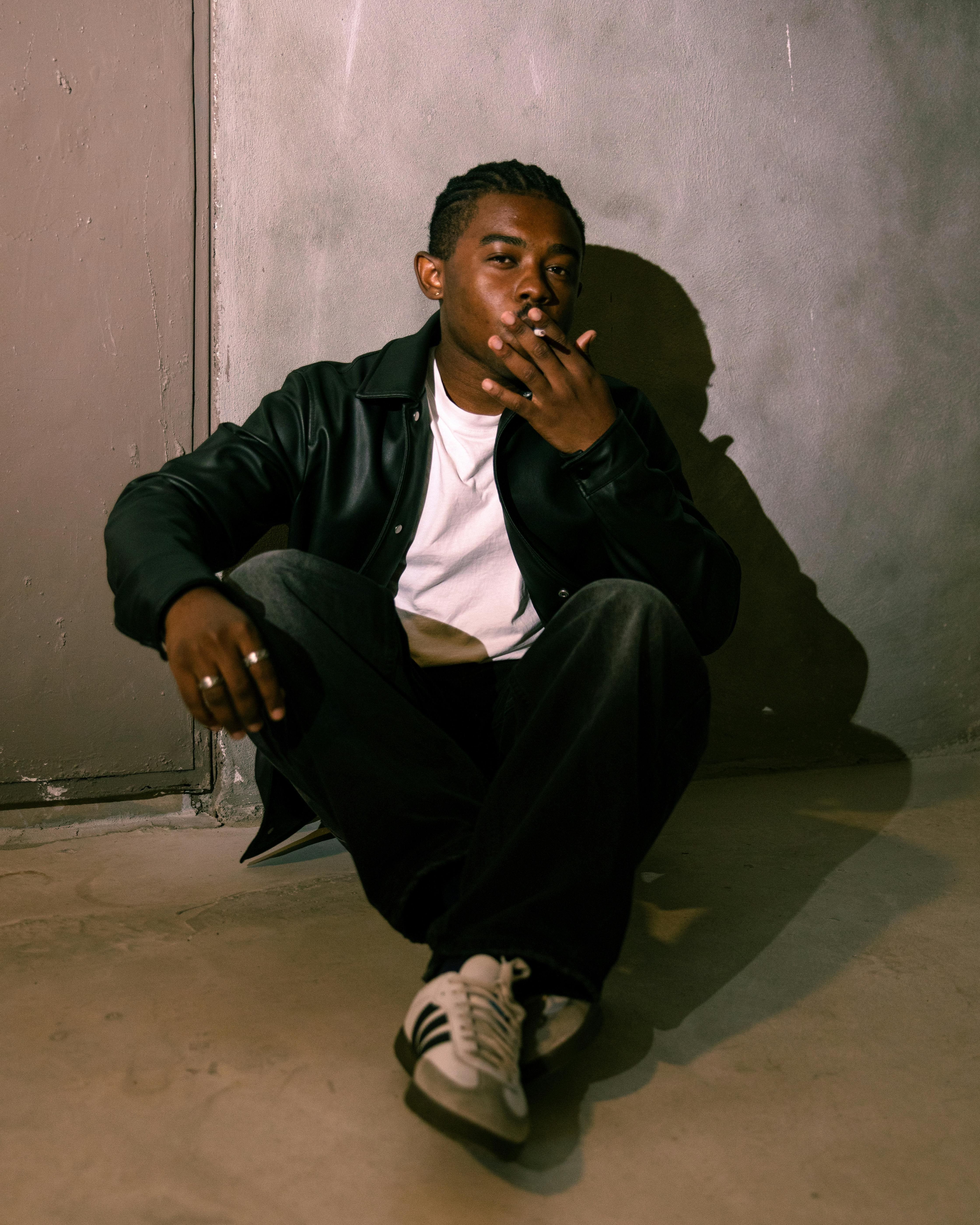 A man sitting on the ground smoking a cigarette · Free Stock Photo