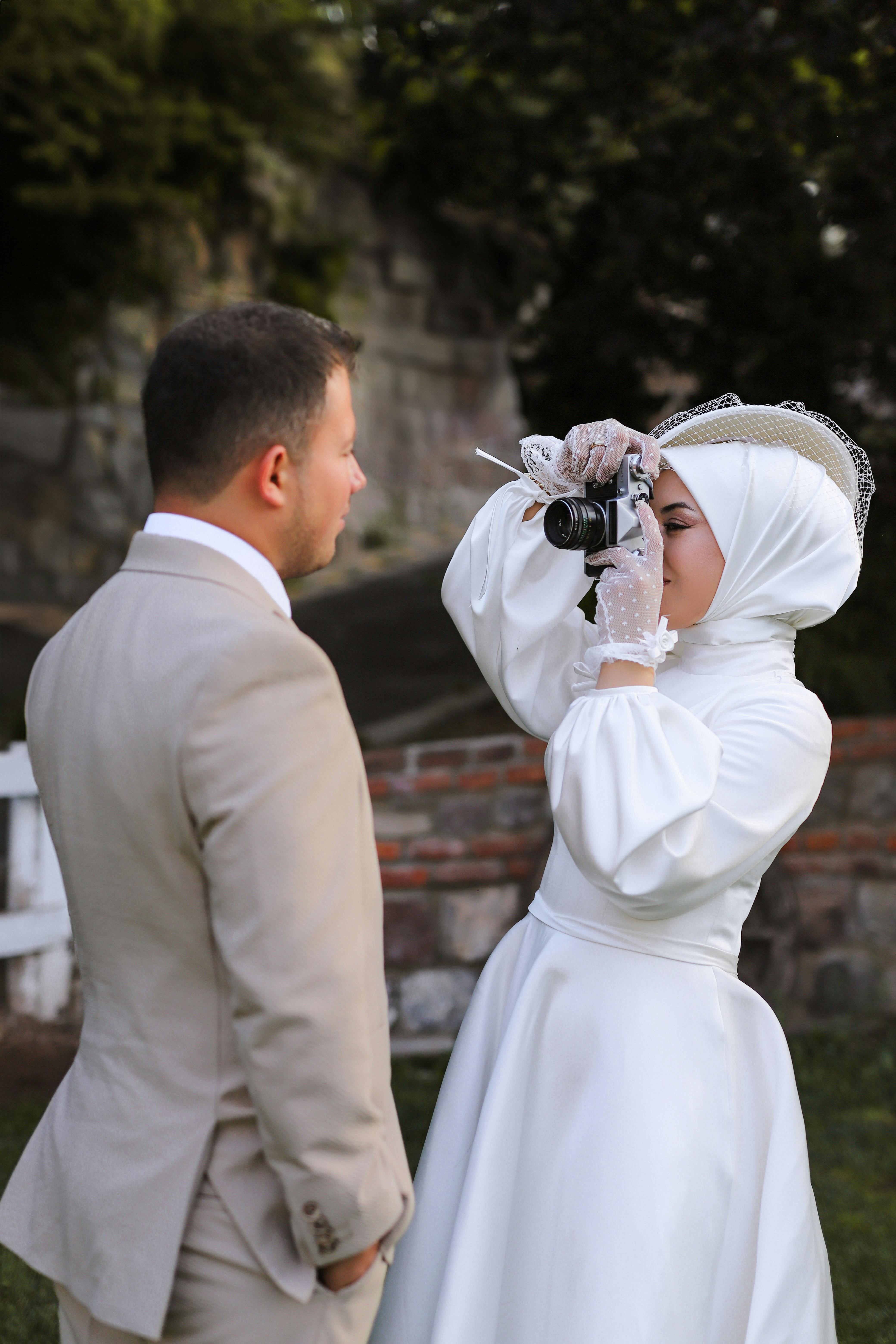 A bride and groom taking pictures with a camera · Free Stock Photo