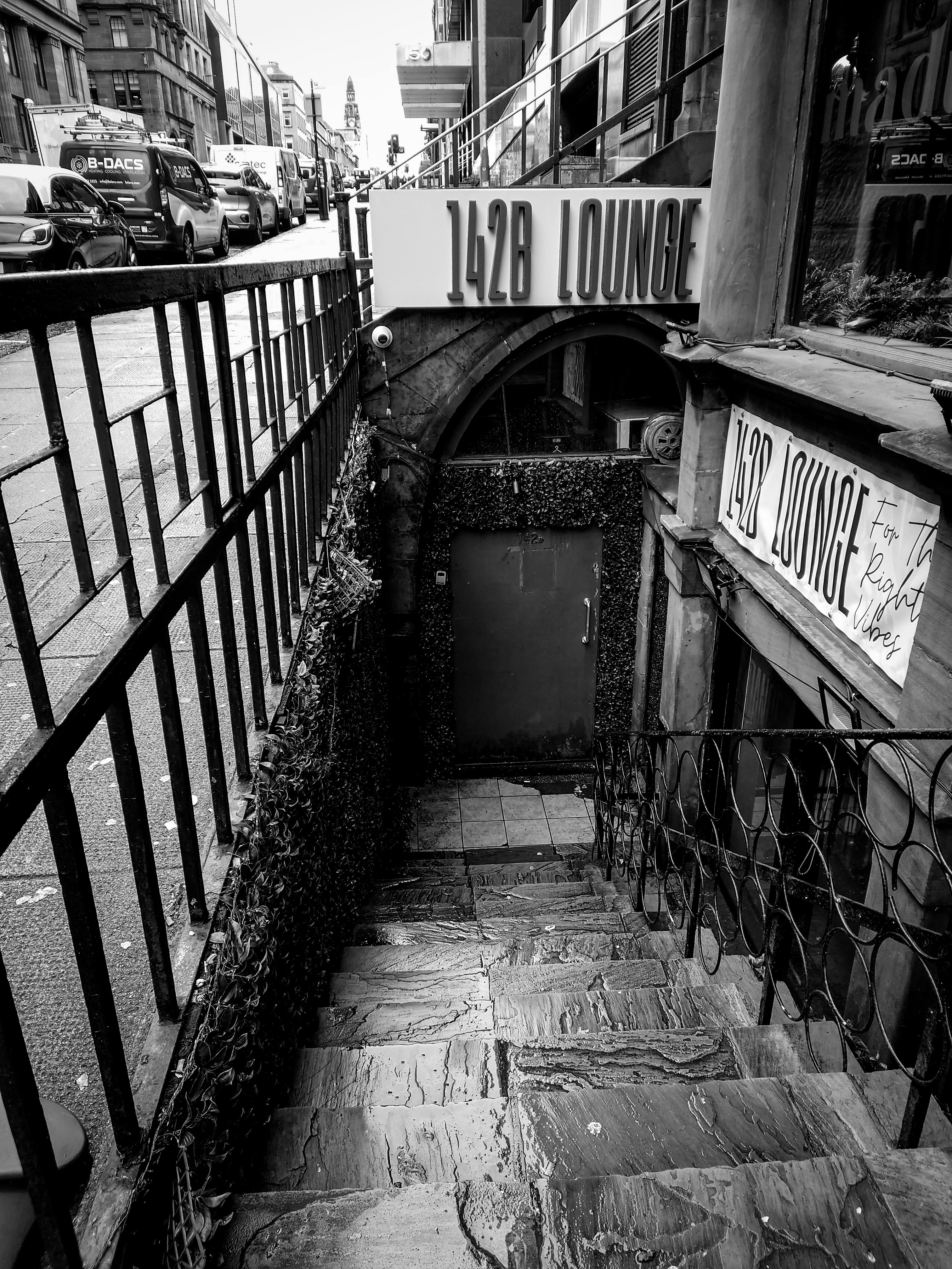 A black and white photo of stairs leading to a bar · Free Stock Photo