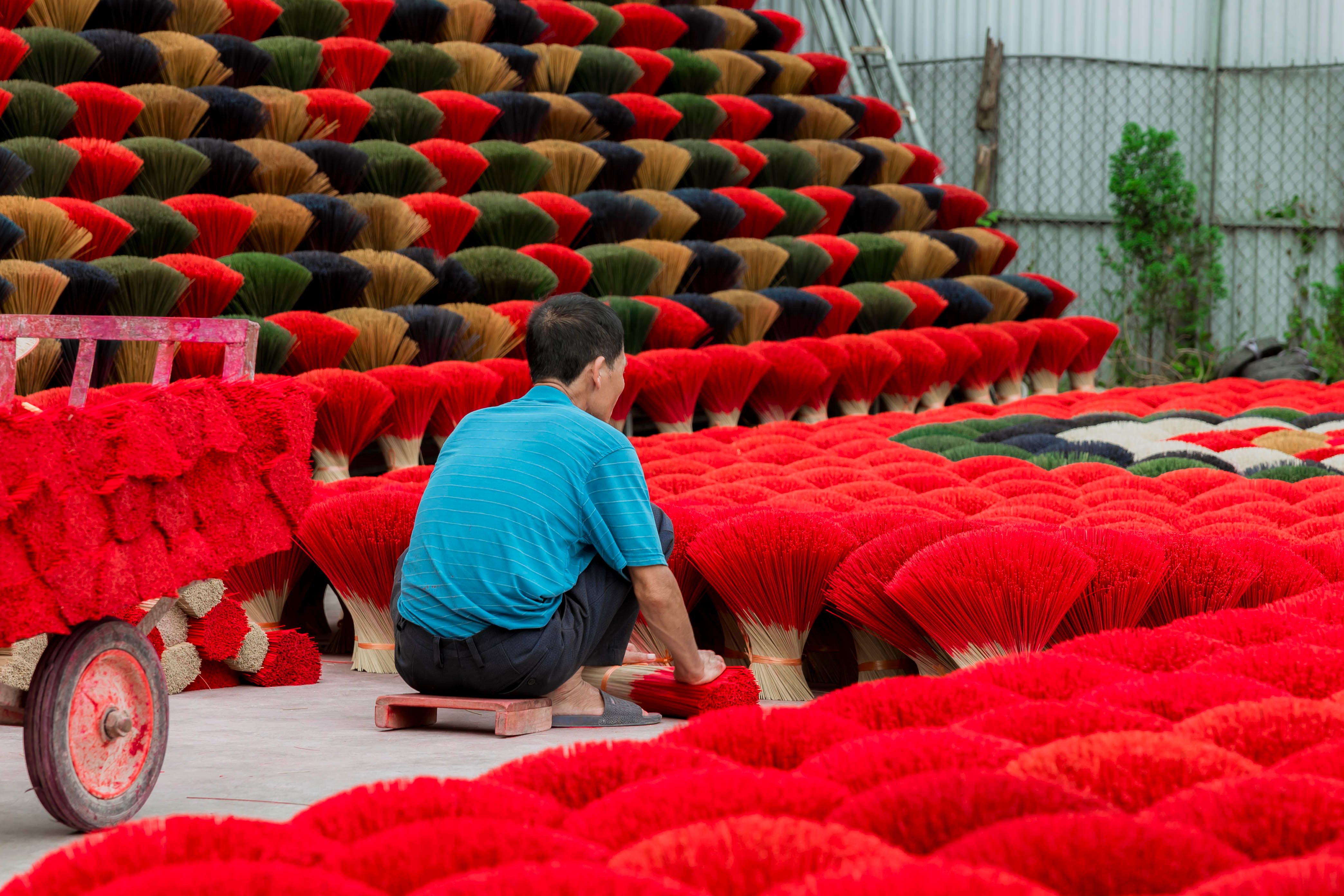 A man is sitting on the floor in front of rows of red rugs · Free Stock ...