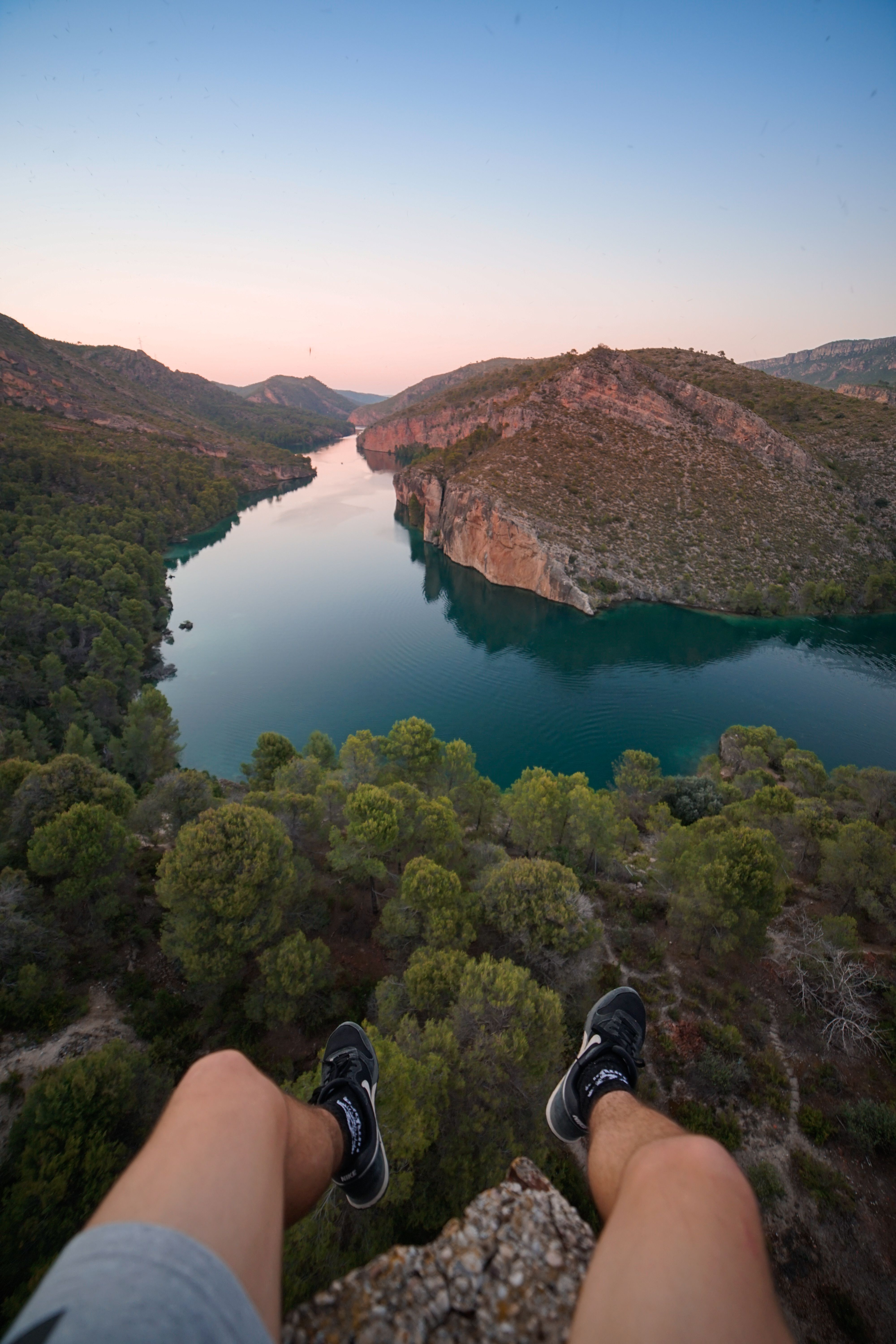 A person's feet are on the edge of a cliff overlooking a lake · Free ...