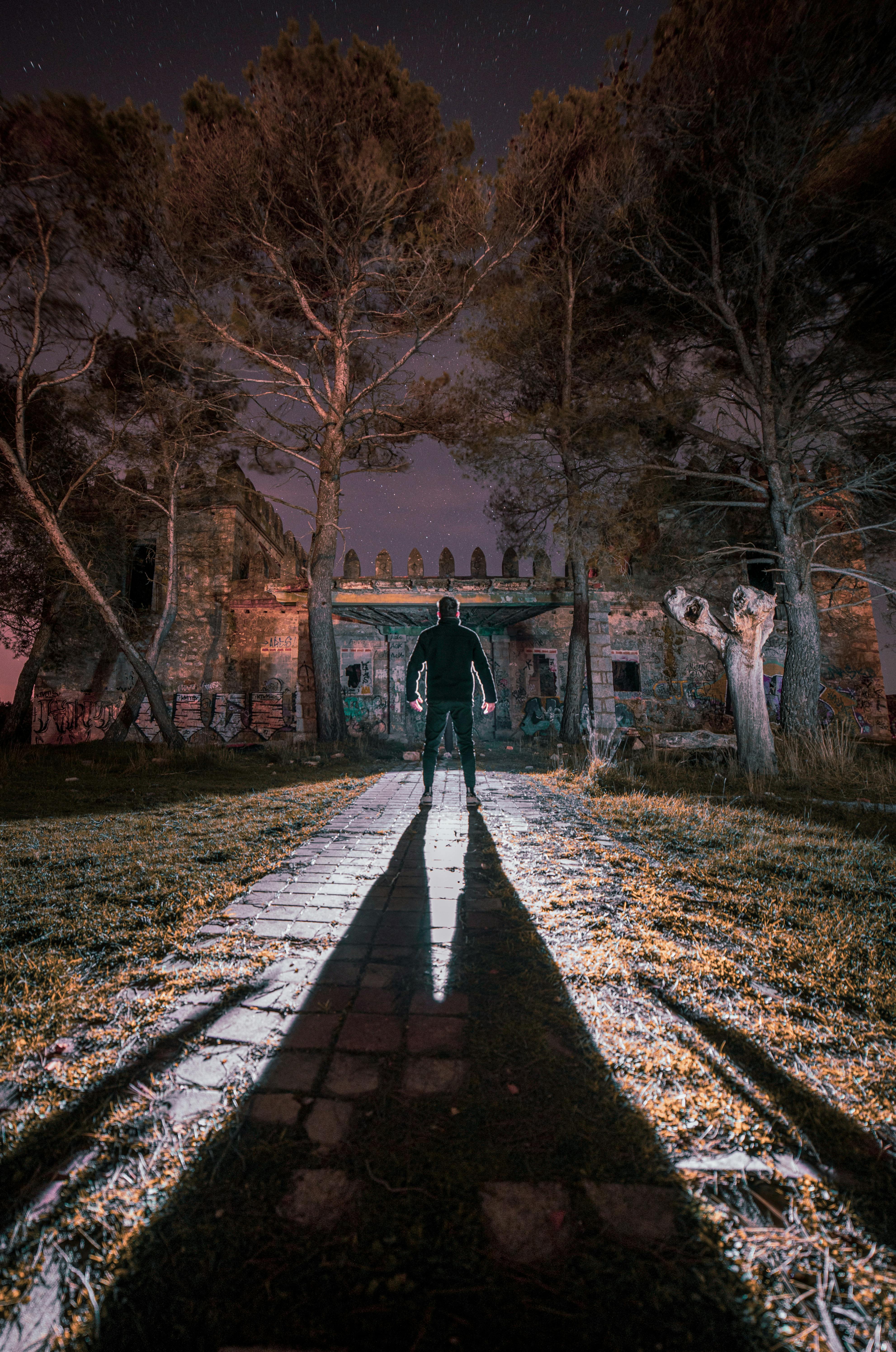 A man standing in the middle of a path with a shadow · Free Stock Photo