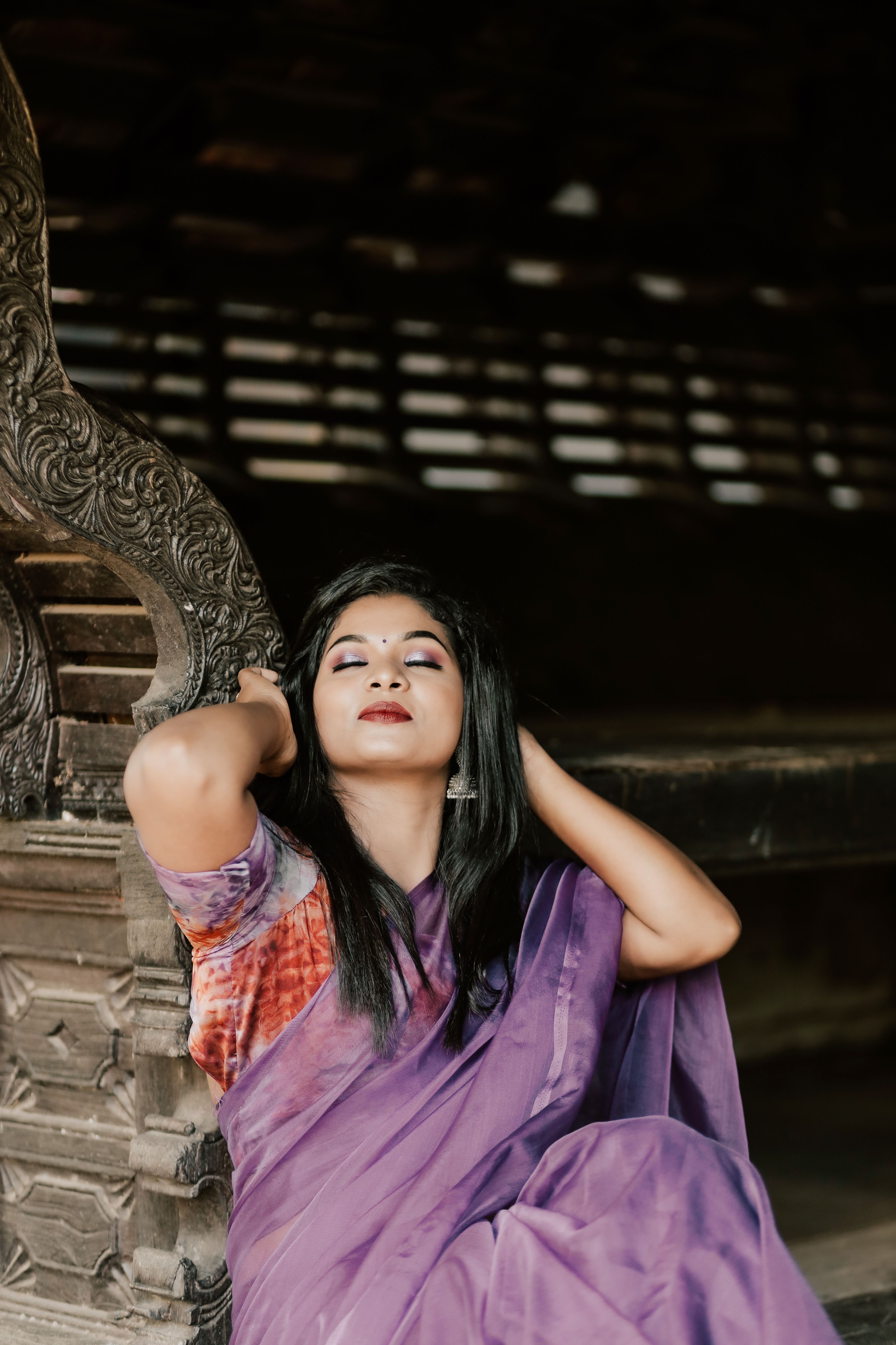 A woman in a purple sari sitting on a wooden bench · Free Stock Photo