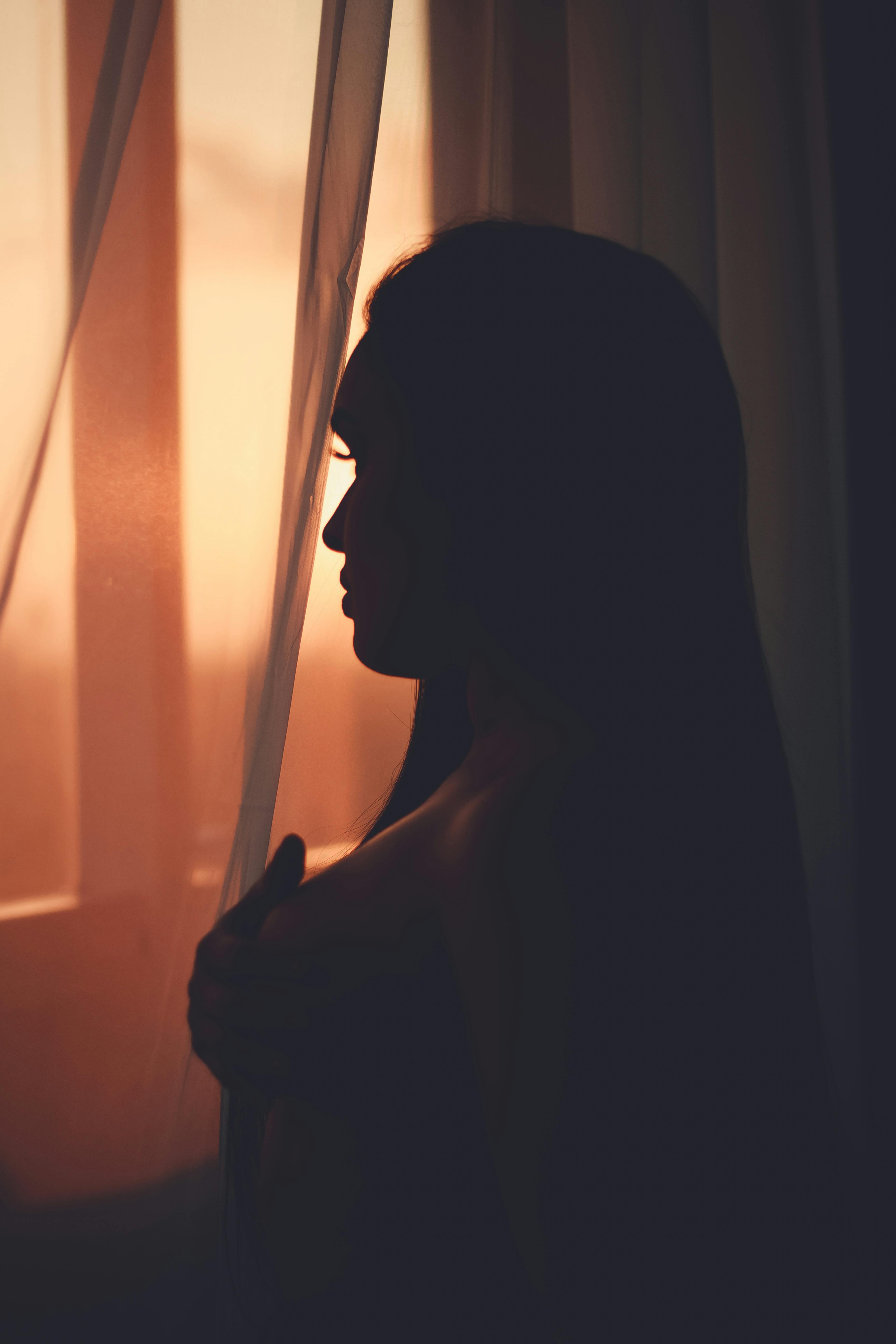 Silhouette of woman looking out window at sunset · Free Stock Photo