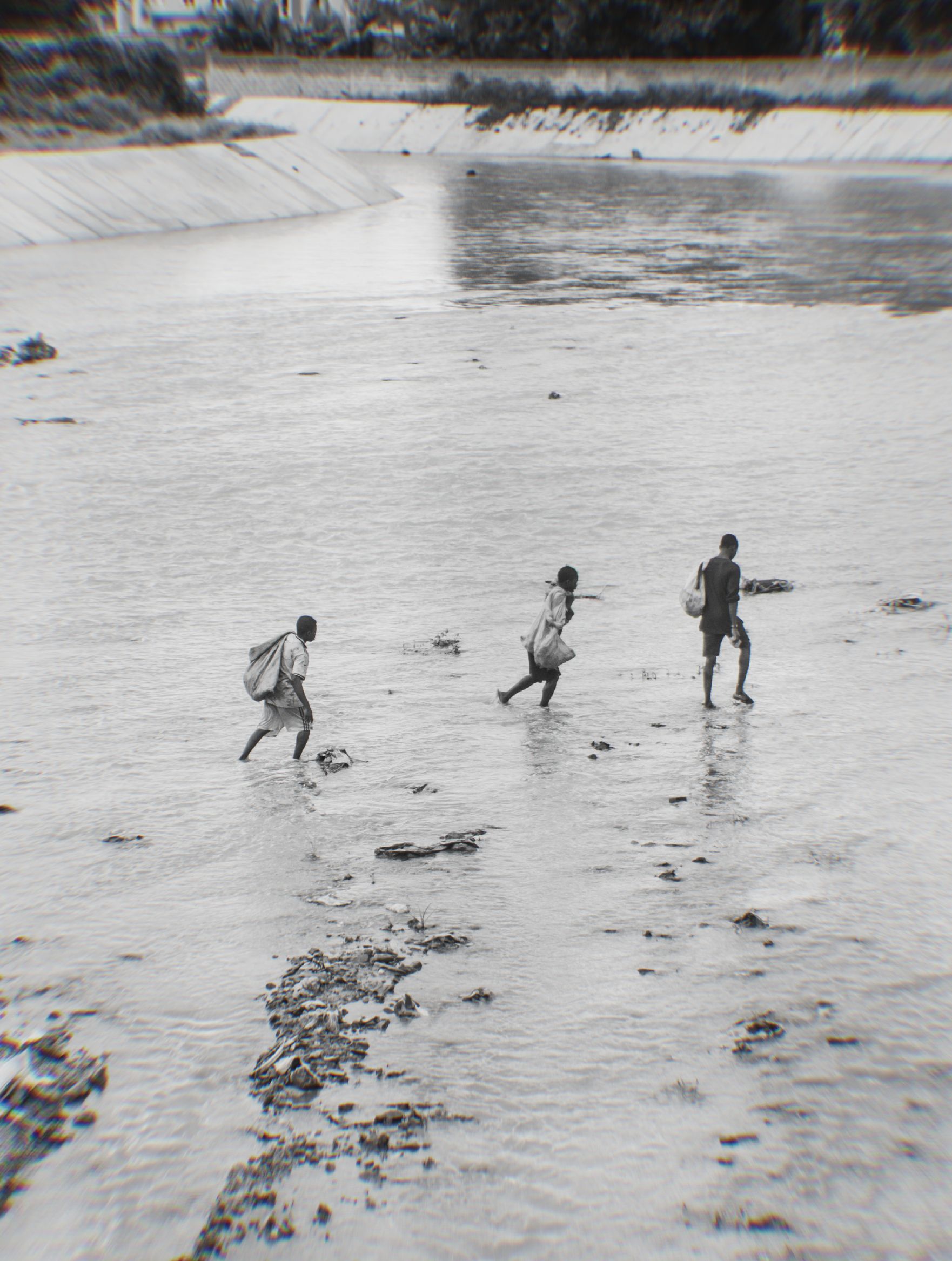 Three boys walking across a river in a black and white photo · Free ...
