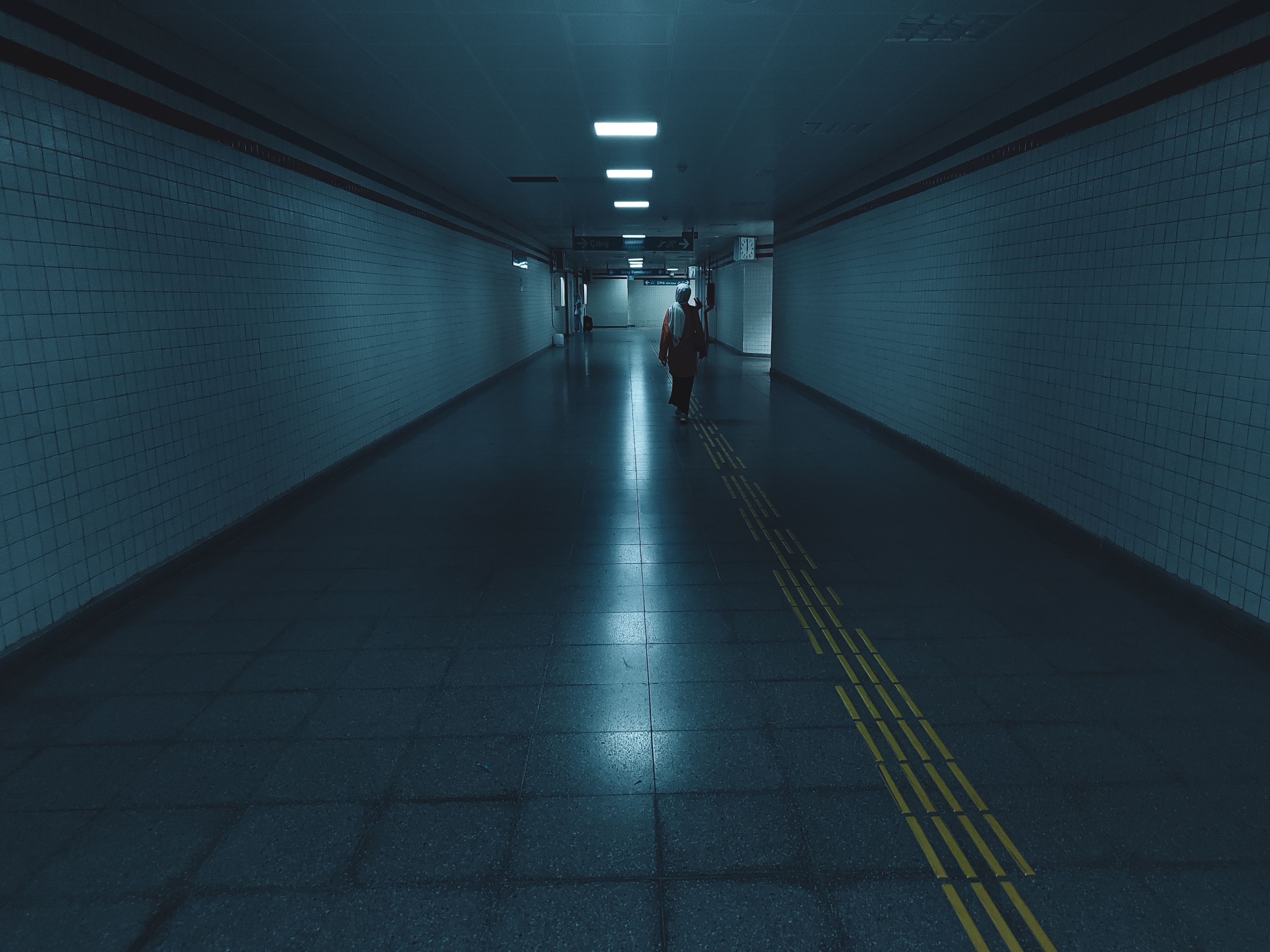 A person walking down a dark hallway in an empty subway · Free Stock Photo