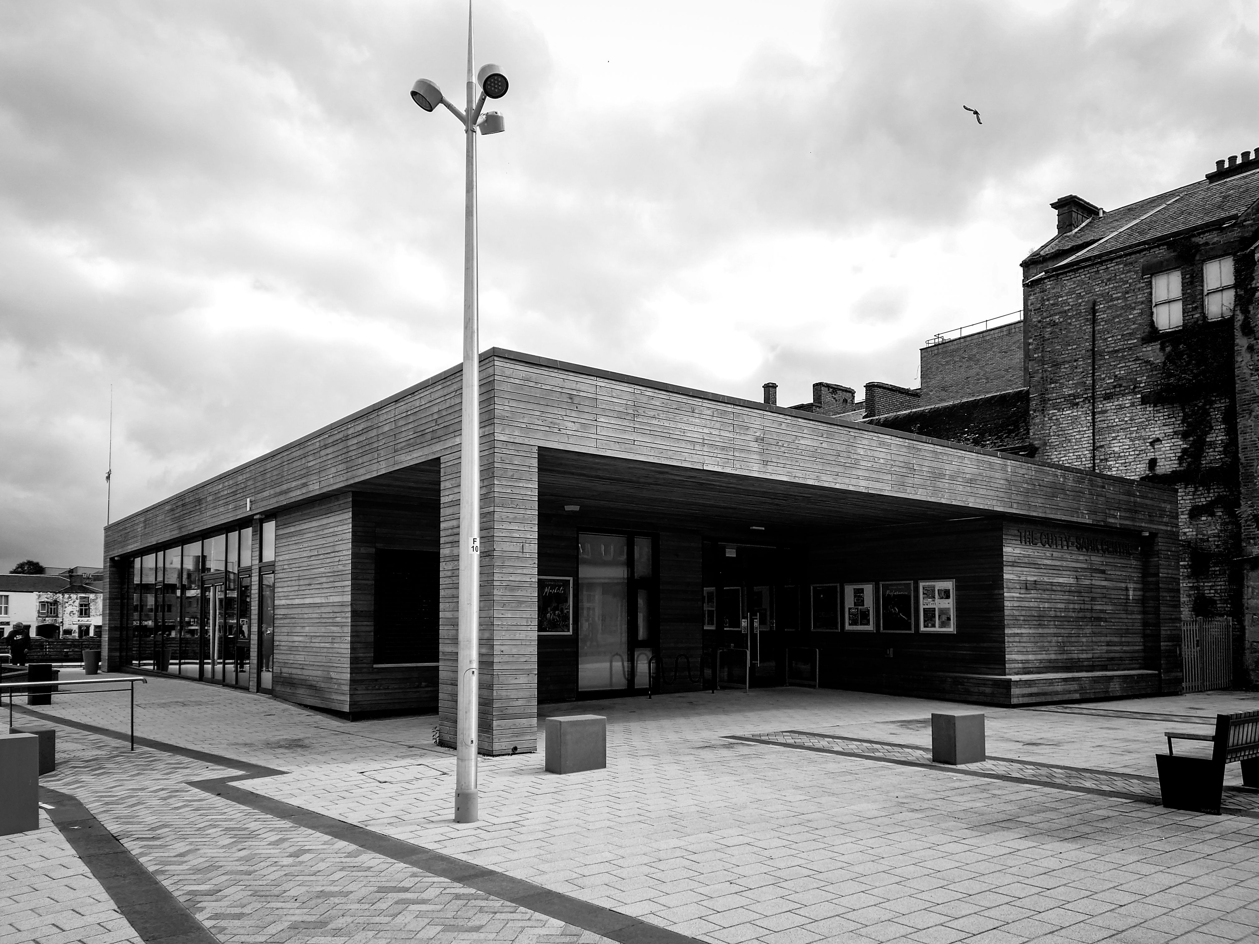 Black and white photo of a building with benches · Free Stock Photo