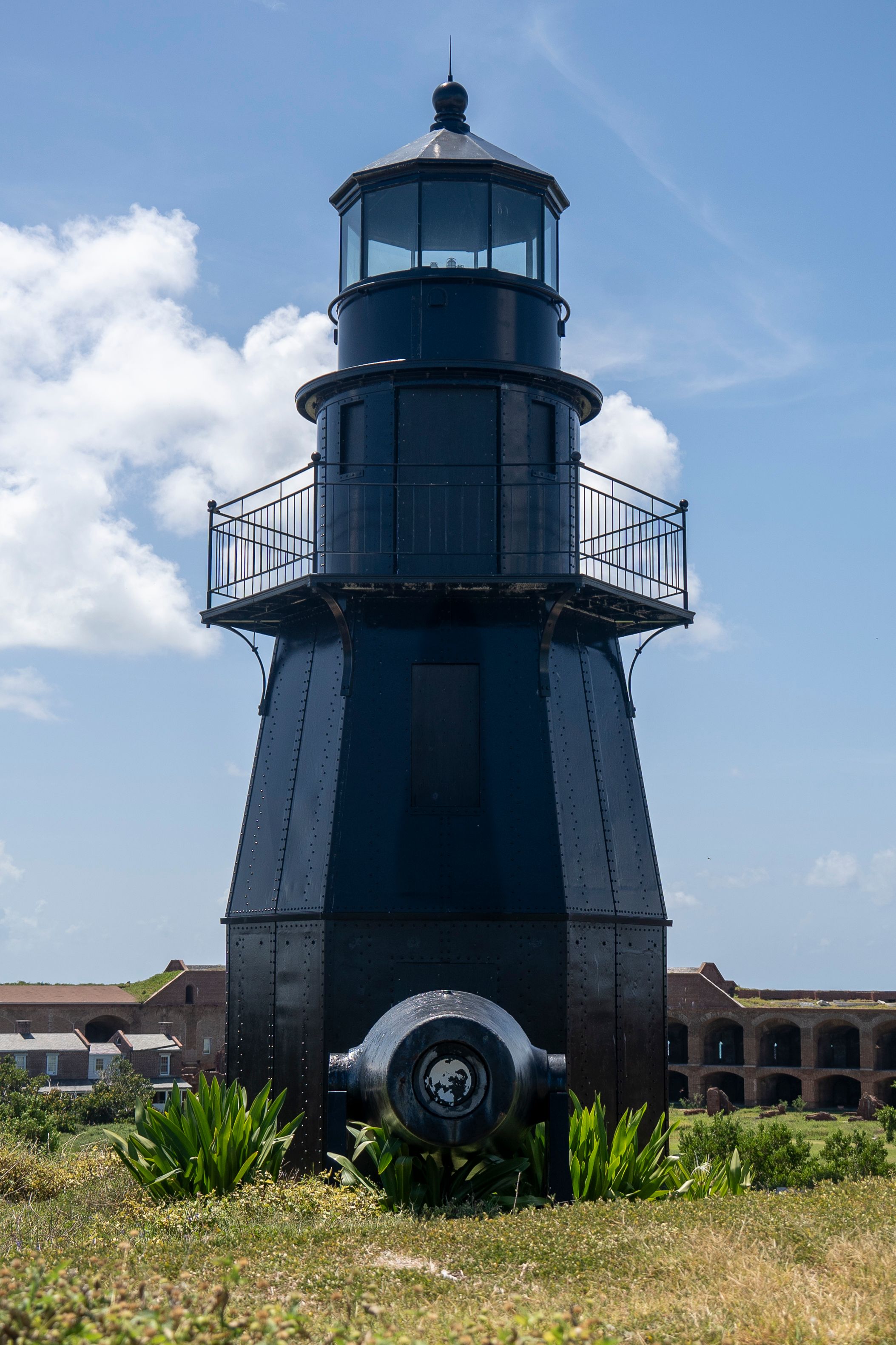 A black lighthouse sits on top of a grassy field · Free Stock Photo