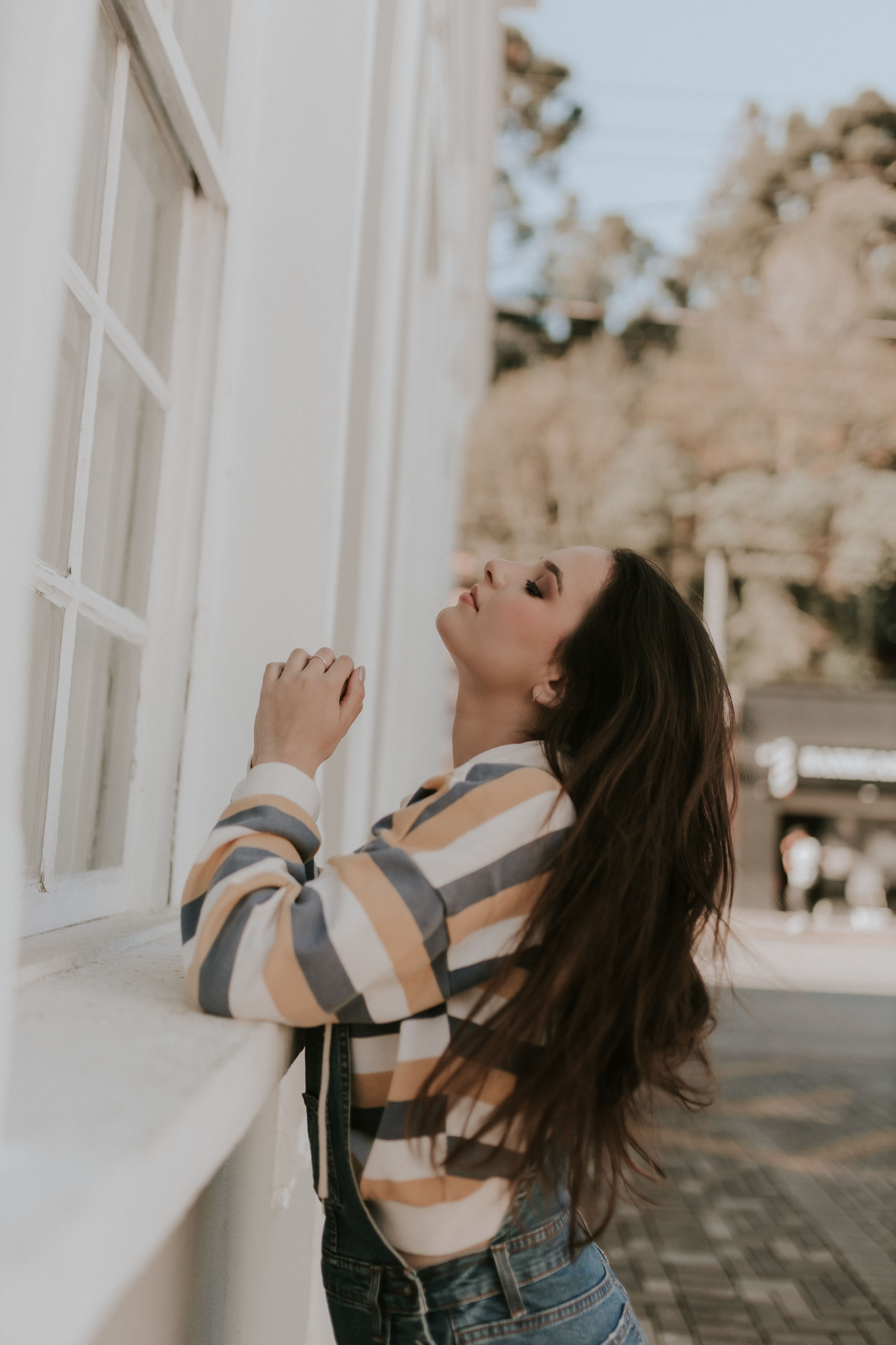 A woman leaning against a window with her arms crossed · Free Stock Photo
