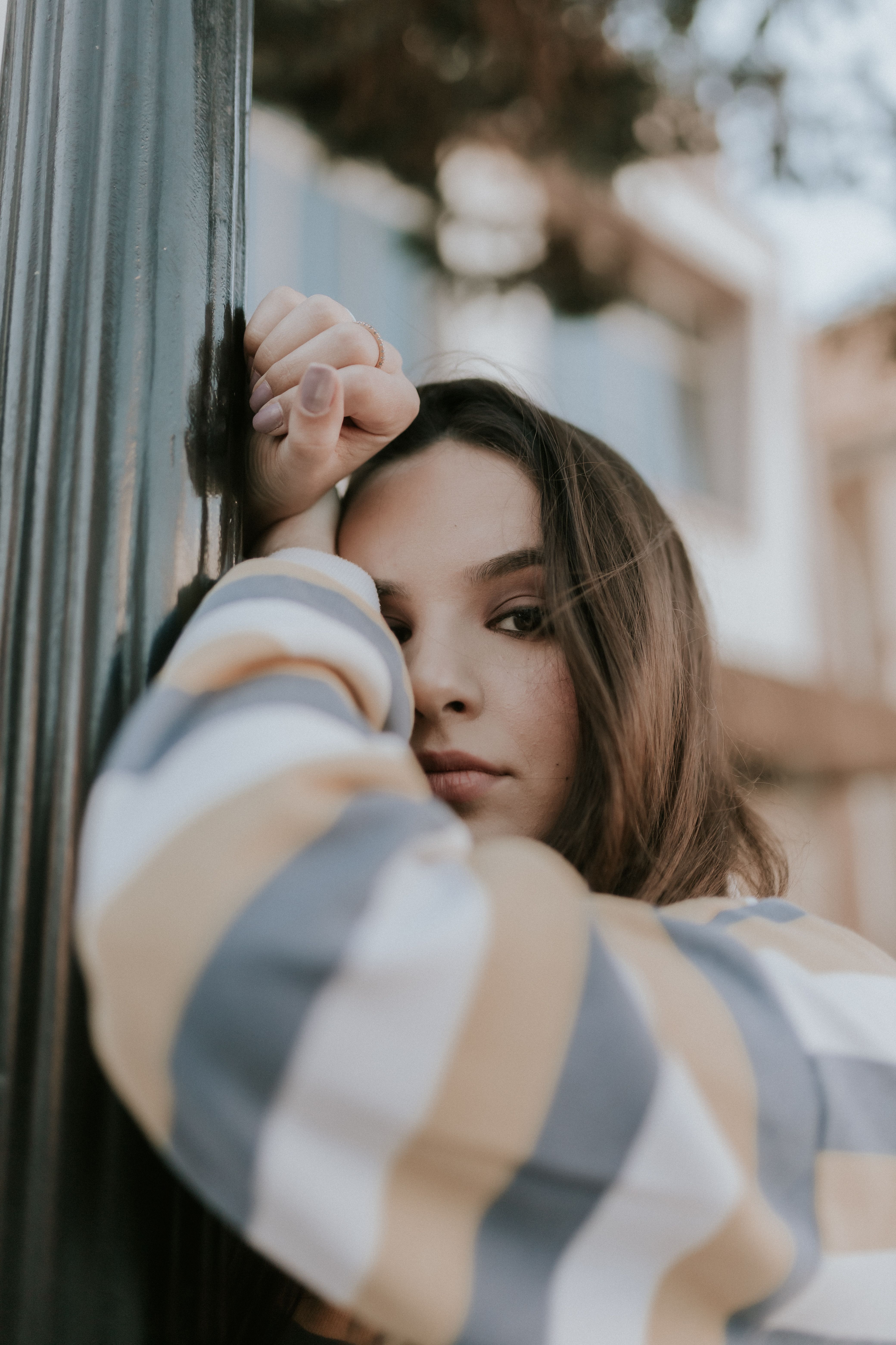 A young woman leaning against a pole · Free Stock Photo