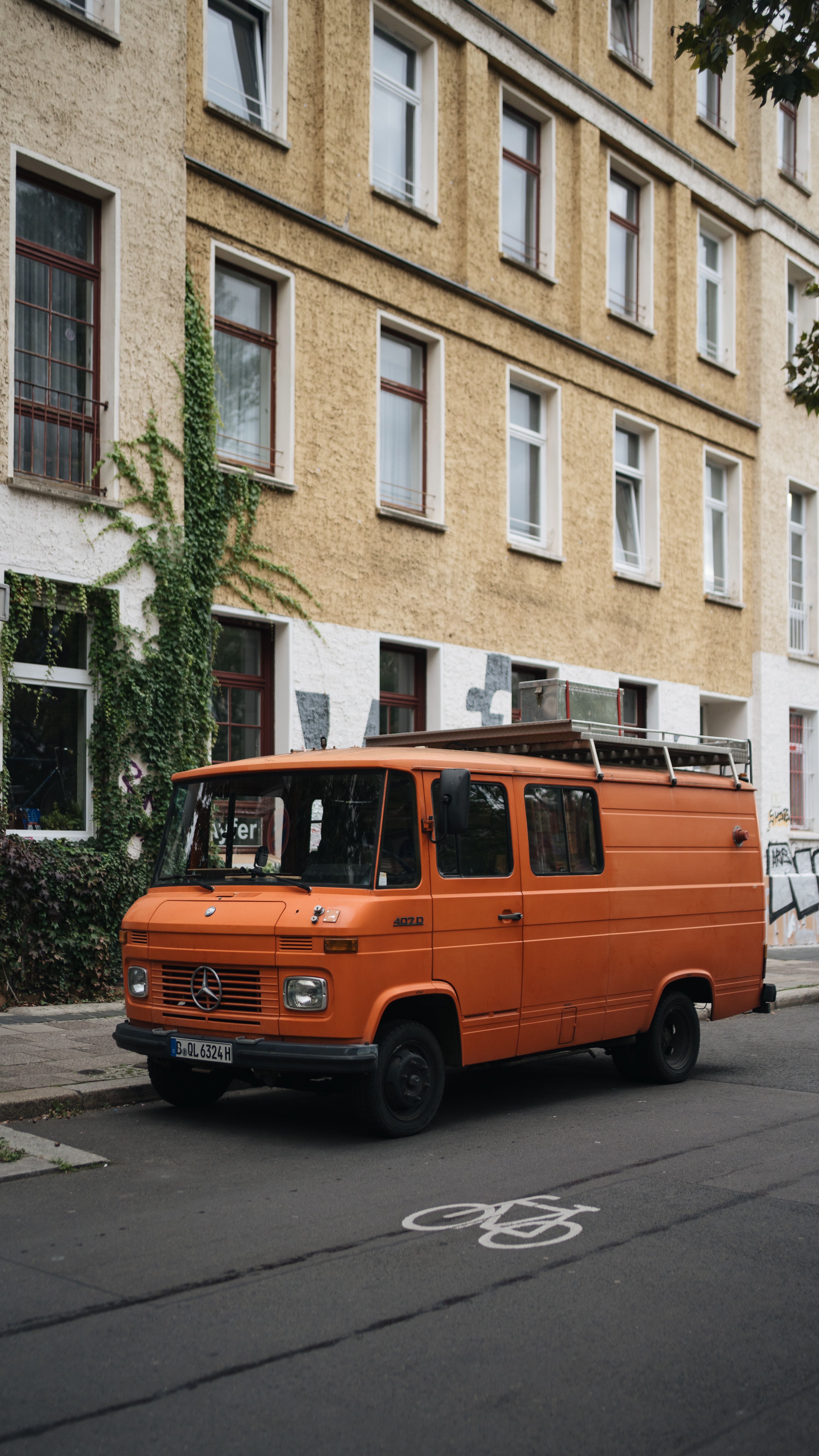 An orange van is parked on the side of the road · Free Stock Photo