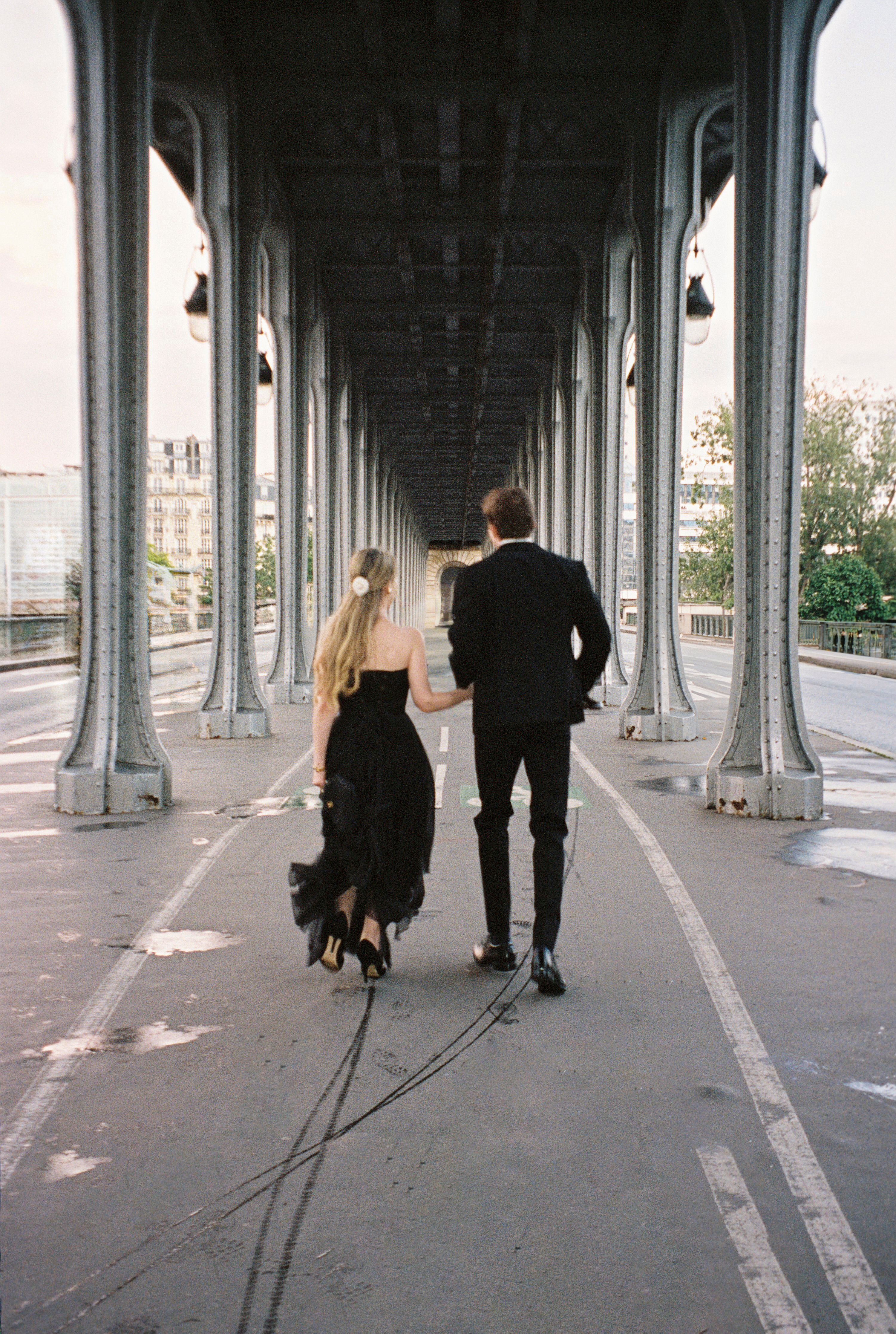 A couple walking under a bridge in black clothing · Free Stock Photo