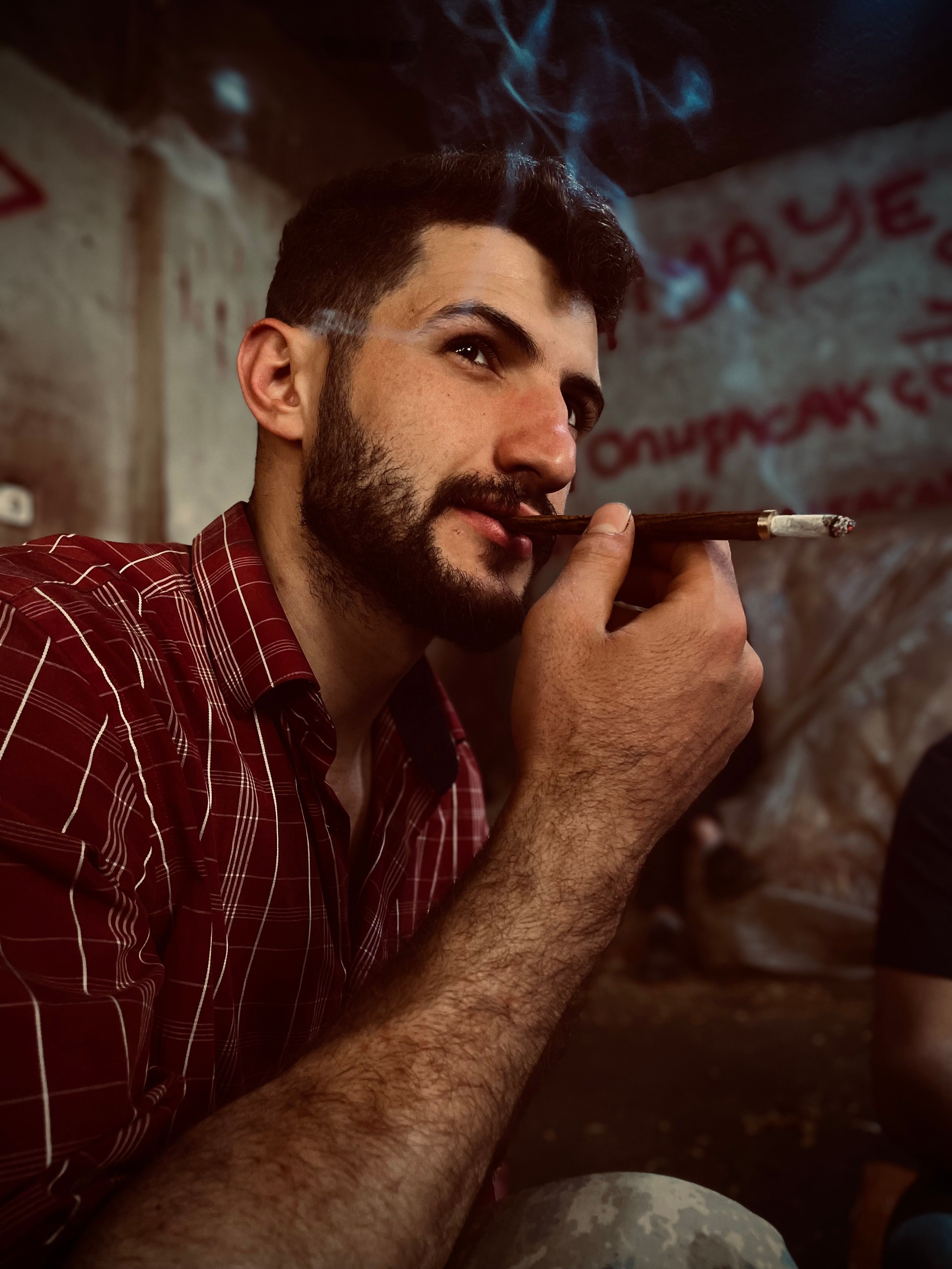 A man smoking a cigarette in front of graffiti · Free Stock Photo