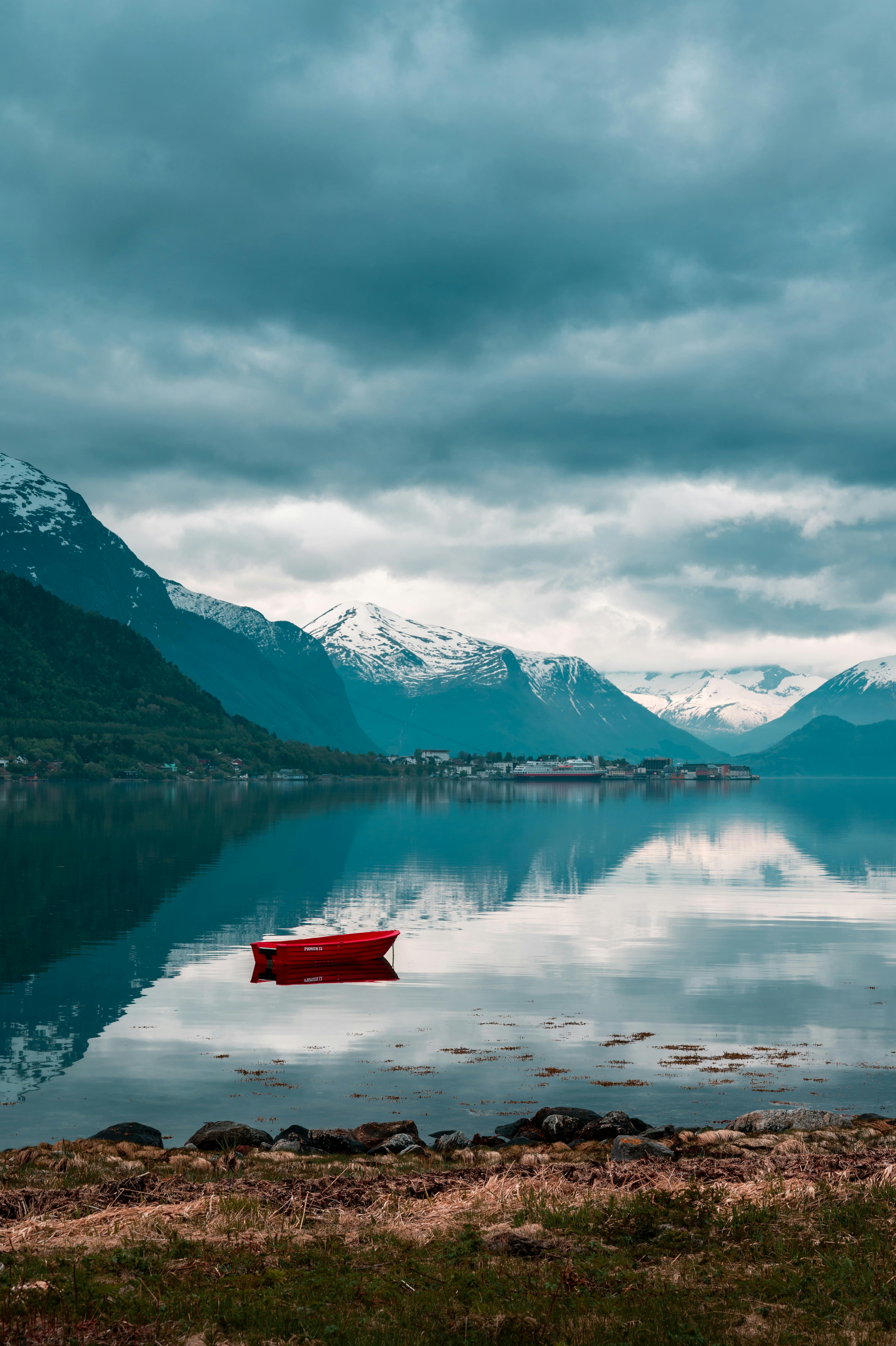 A red boat on the water with mountains in the background · Free Stock Photo