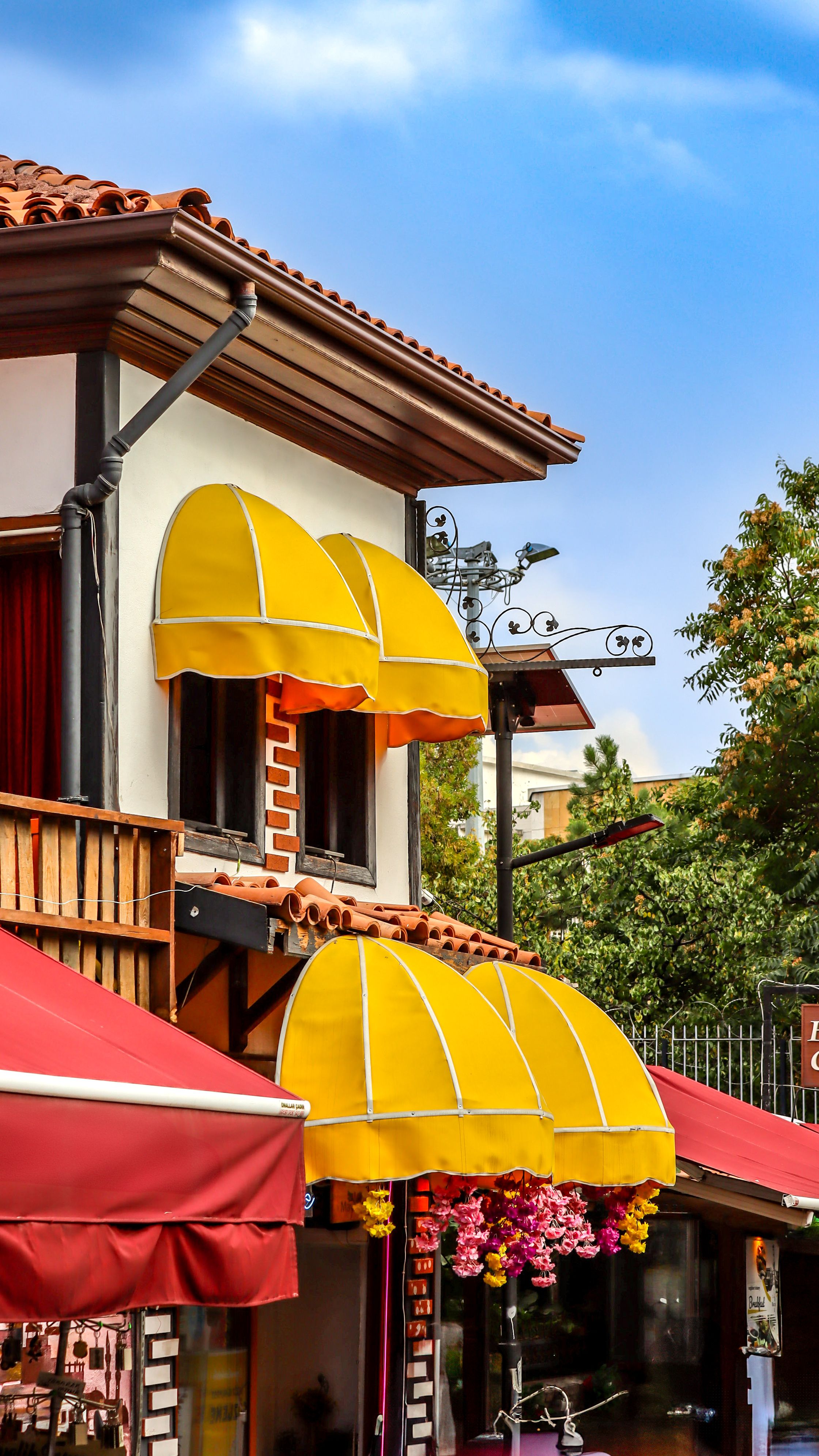 A restaurant with yellow awnings and red umbrellas · Free Stock Photo