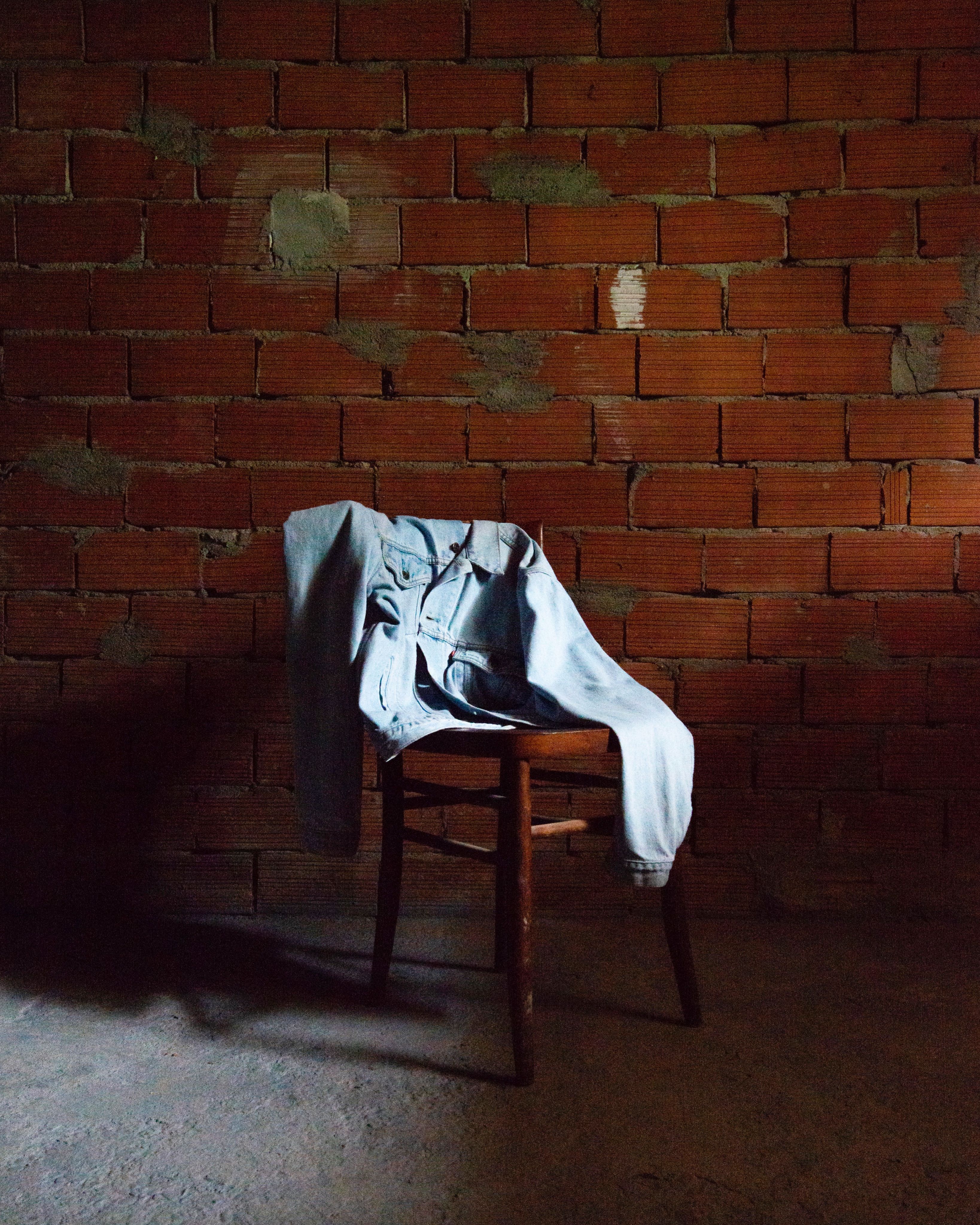 A jacket on a chair in front of a brick wall · Free Stock Photo