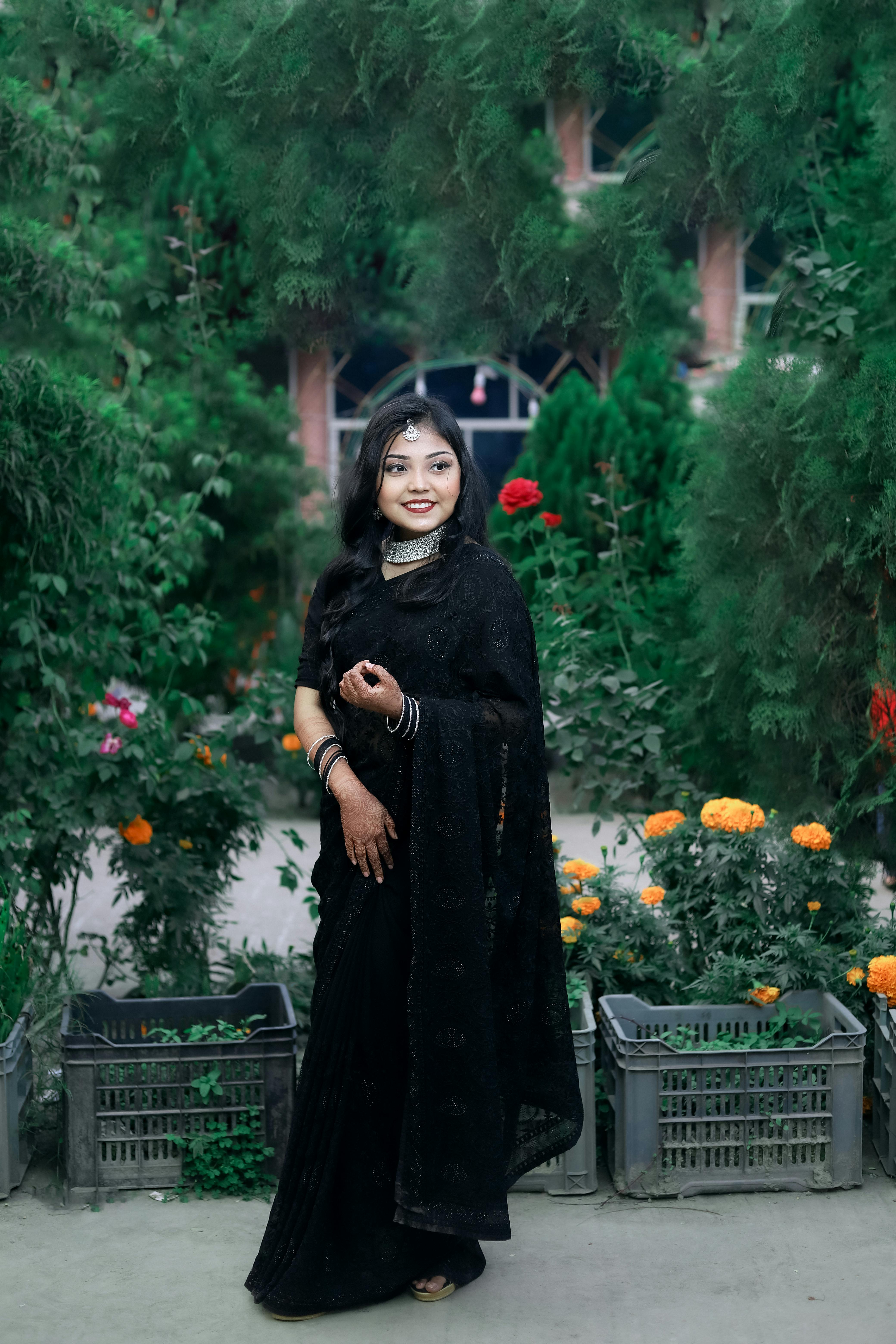 A woman in black sari standing in front of flowers · Free Stock Photo