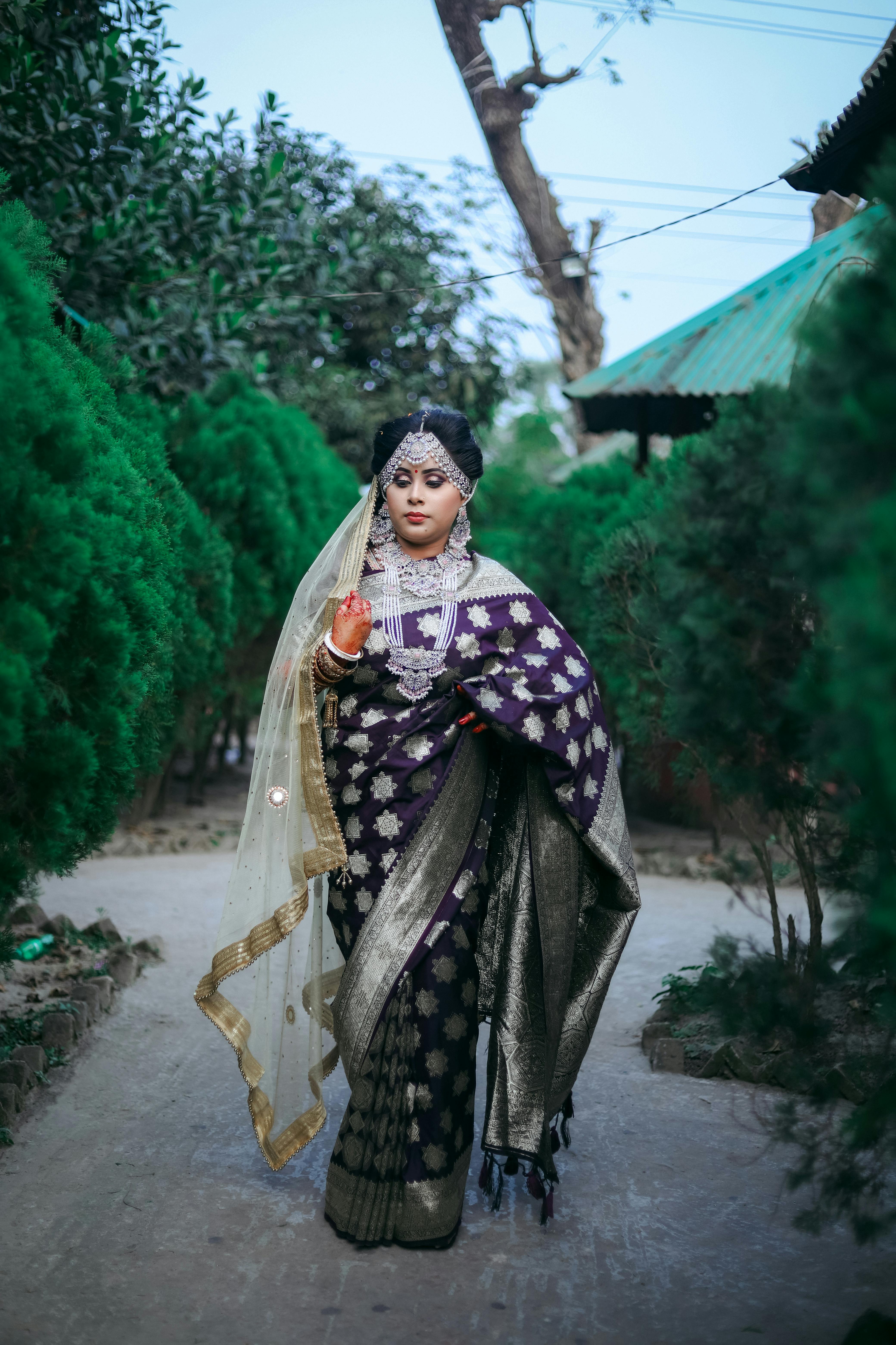 A woman in a purple and gold sari walking down a path · Free Stock Photo