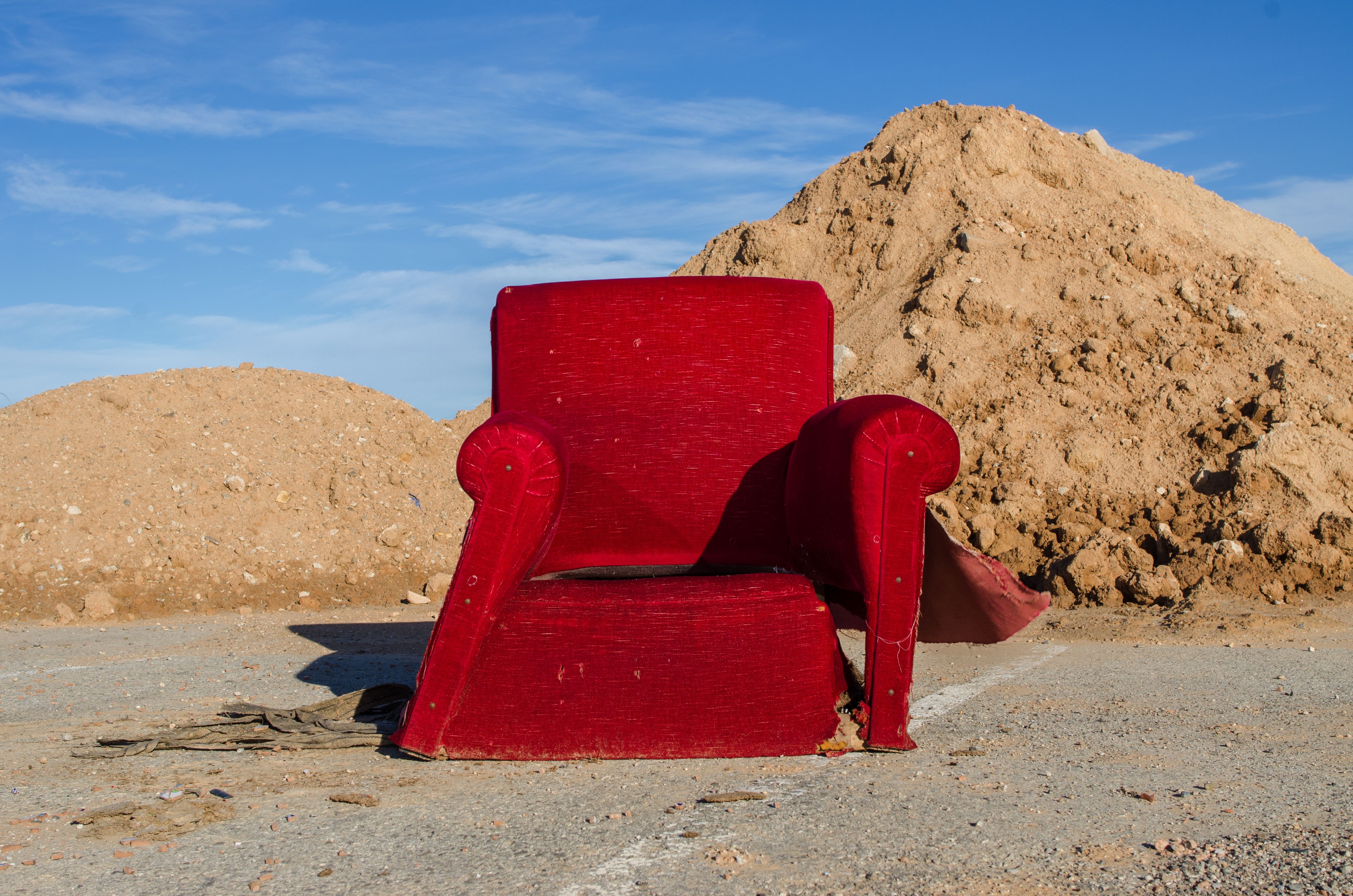 A red chair sitting in the middle of a pile of dirt · Free Stock Photo