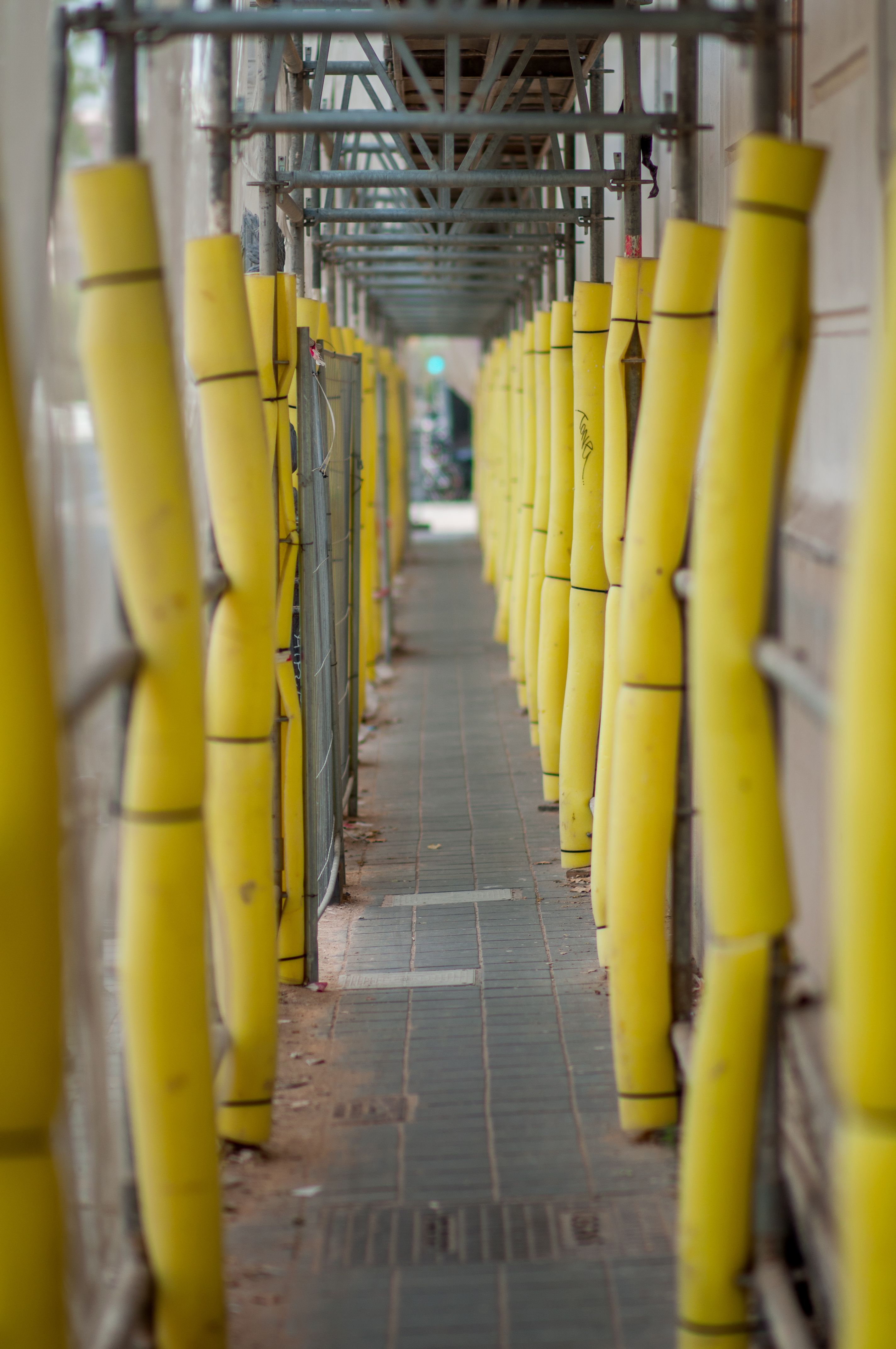 A walkway with yellow poles and yellow scaffolding · Free Stock Photo