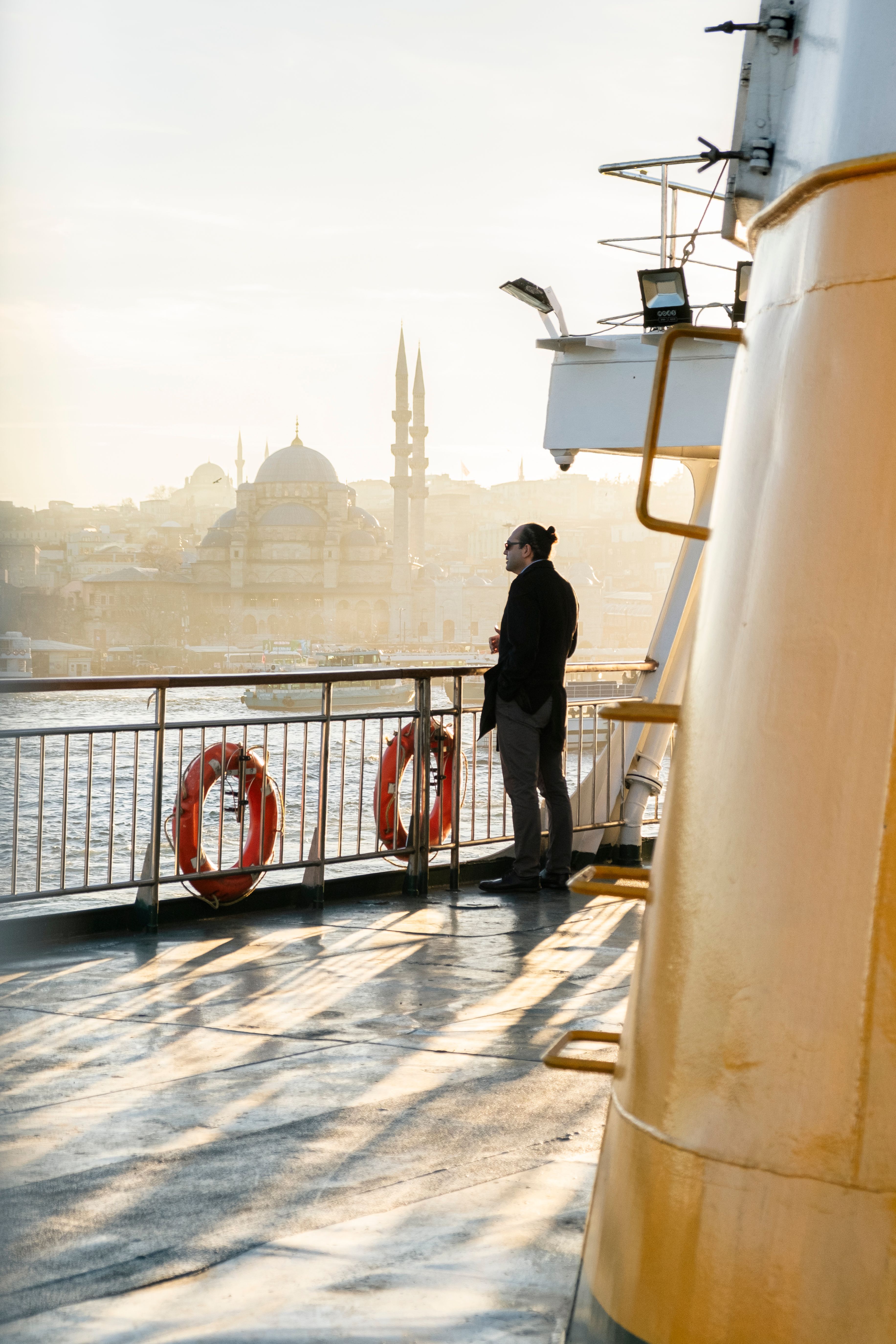 A man standing on the deck of a ship looking out at the water · Free ...