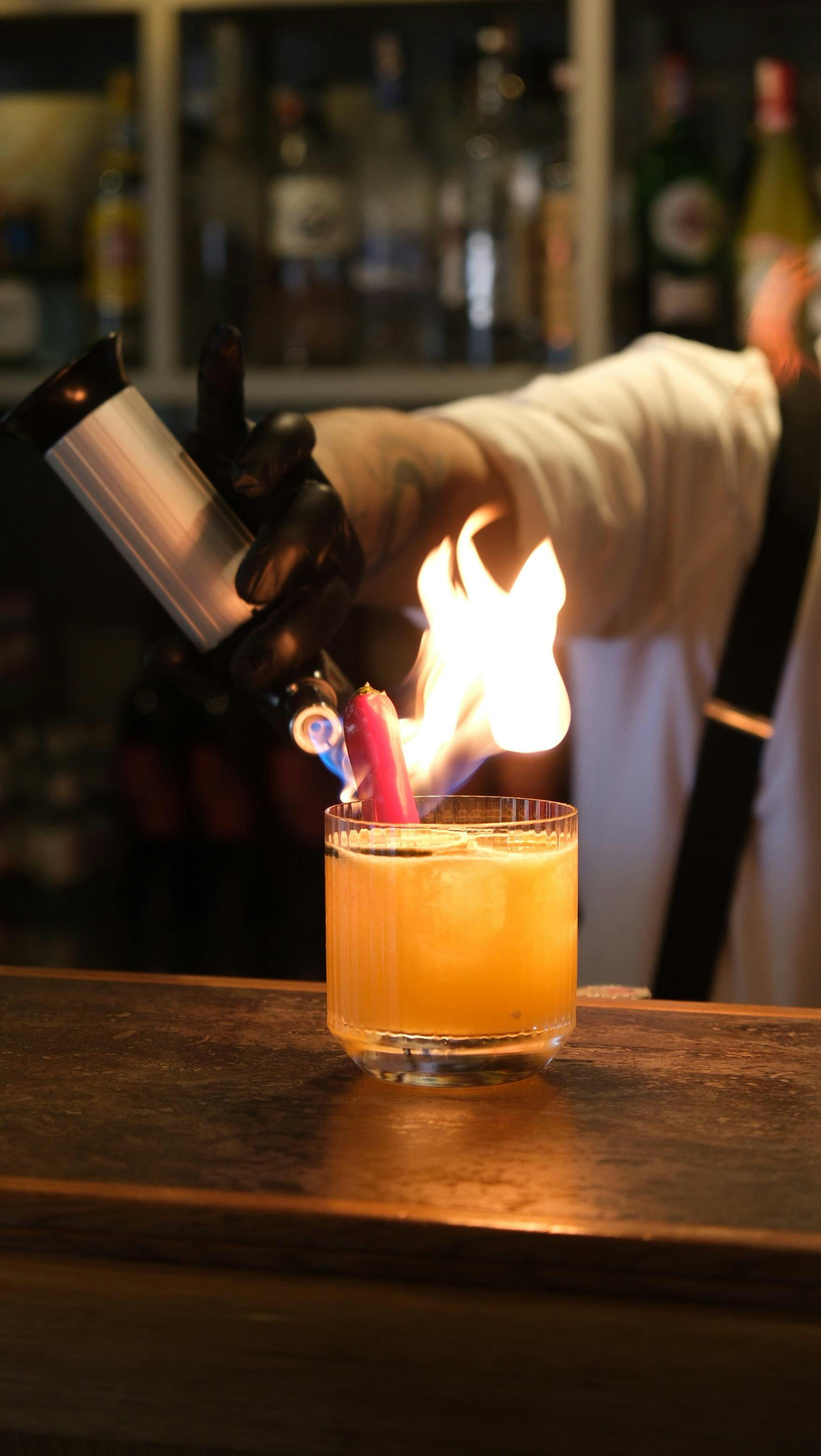 A bartender is pouring a drink with flames · Free Stock Photo