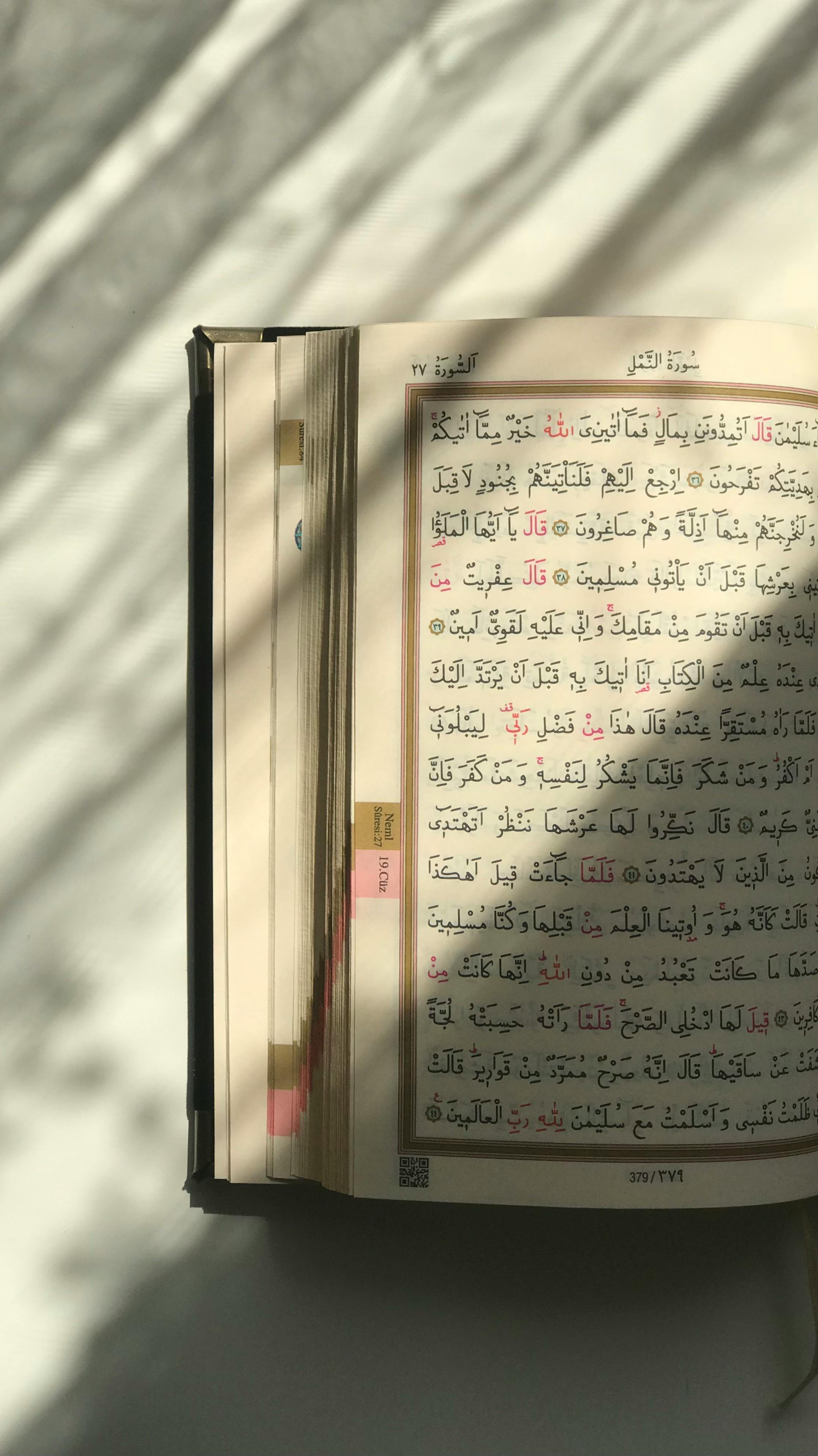 A book open to the quran with the sun shining through · Free Stock Photo