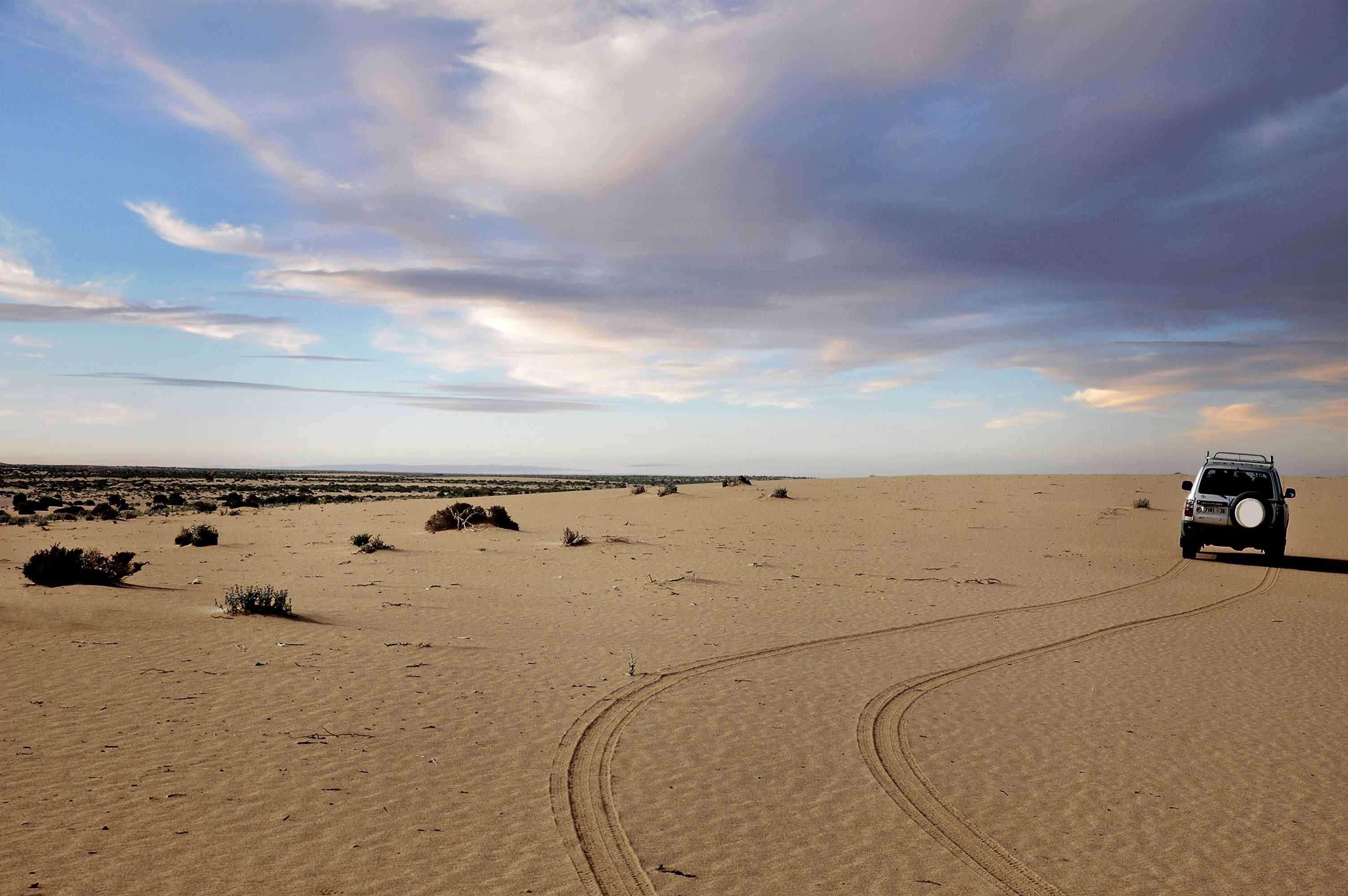 A car driving through the desert with tracks · Free Stock Photo