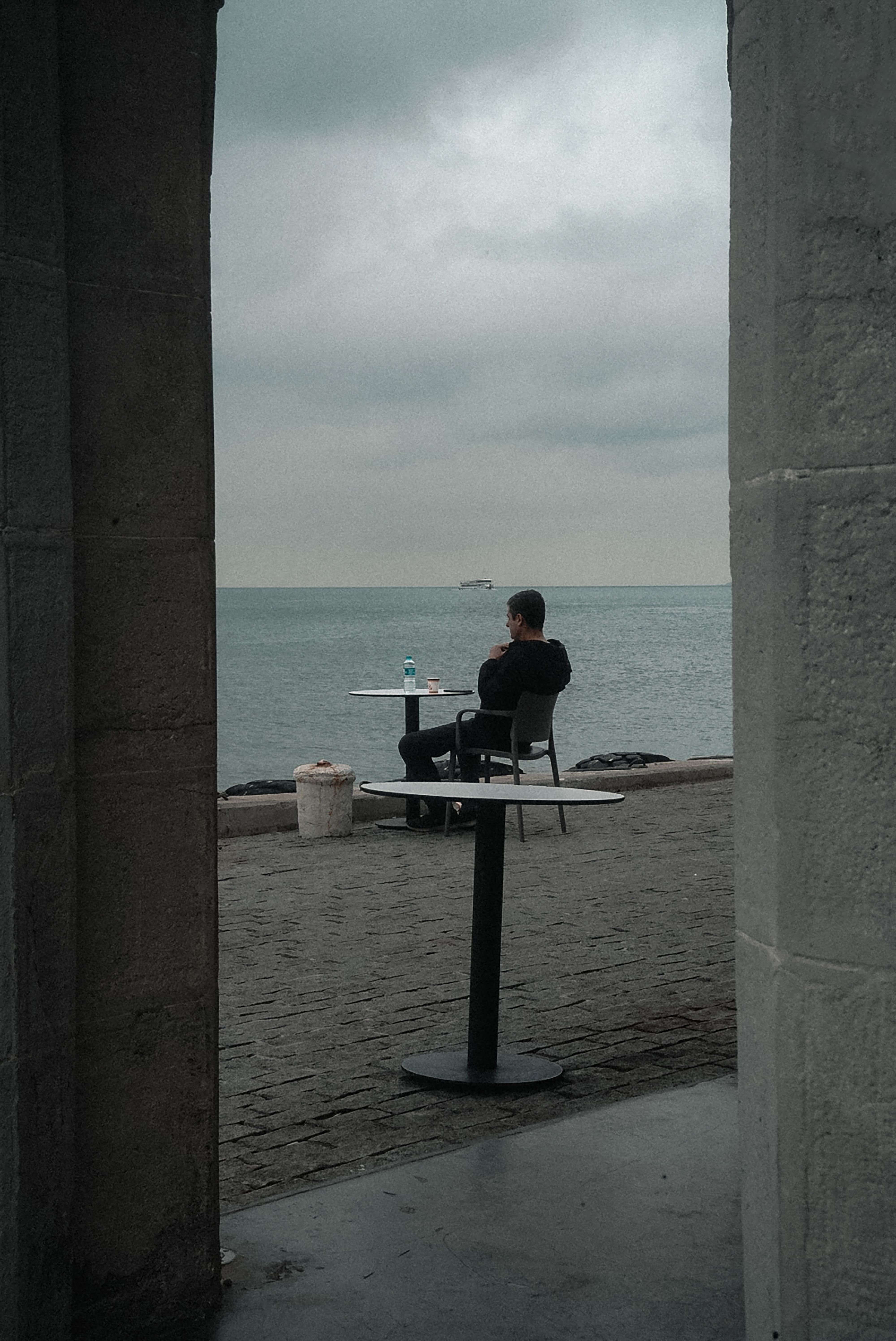 A man sitting at a table in front of the ocean · Free Stock Photo