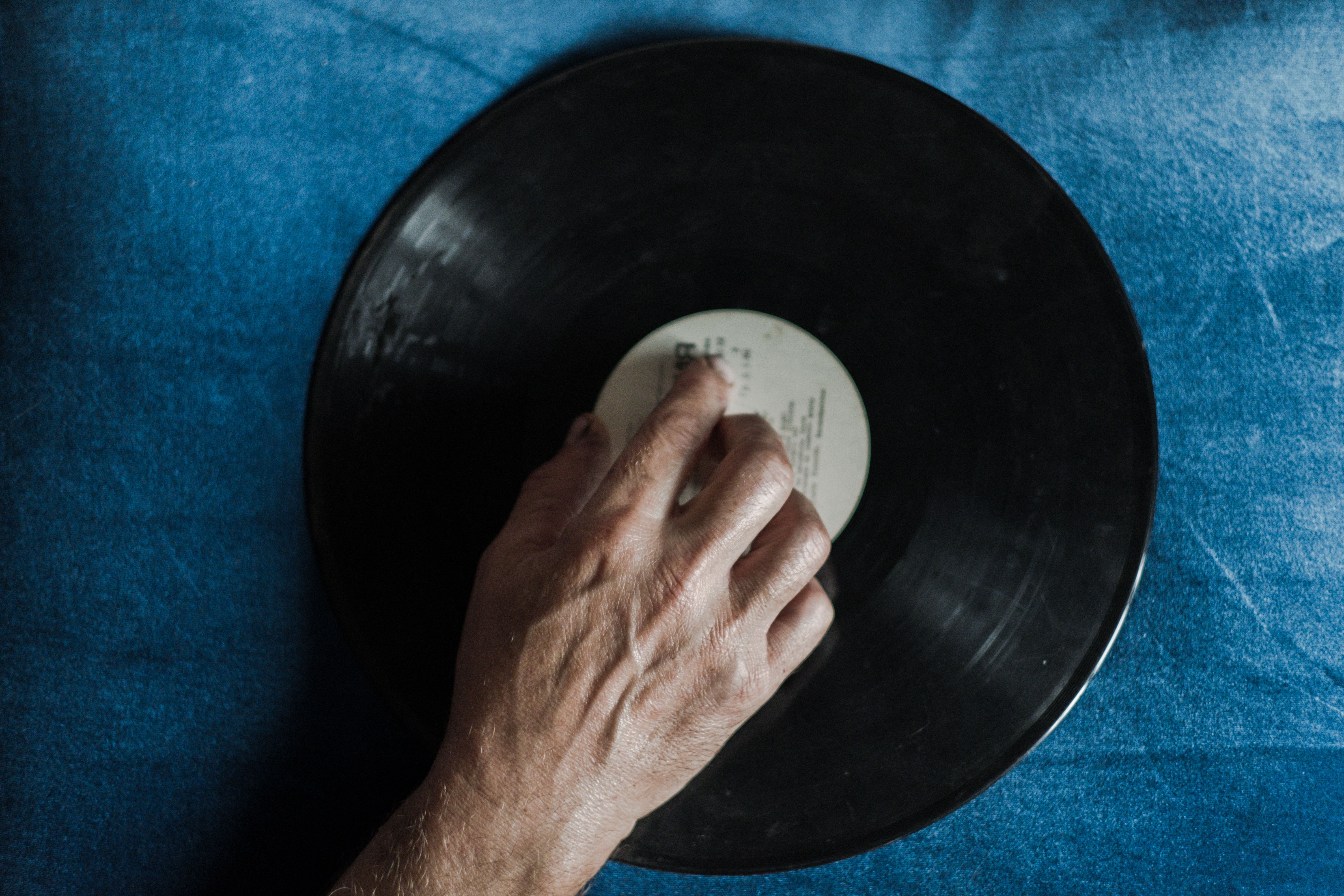 A person's hand holding a record on a blue background · Free Stock Photo